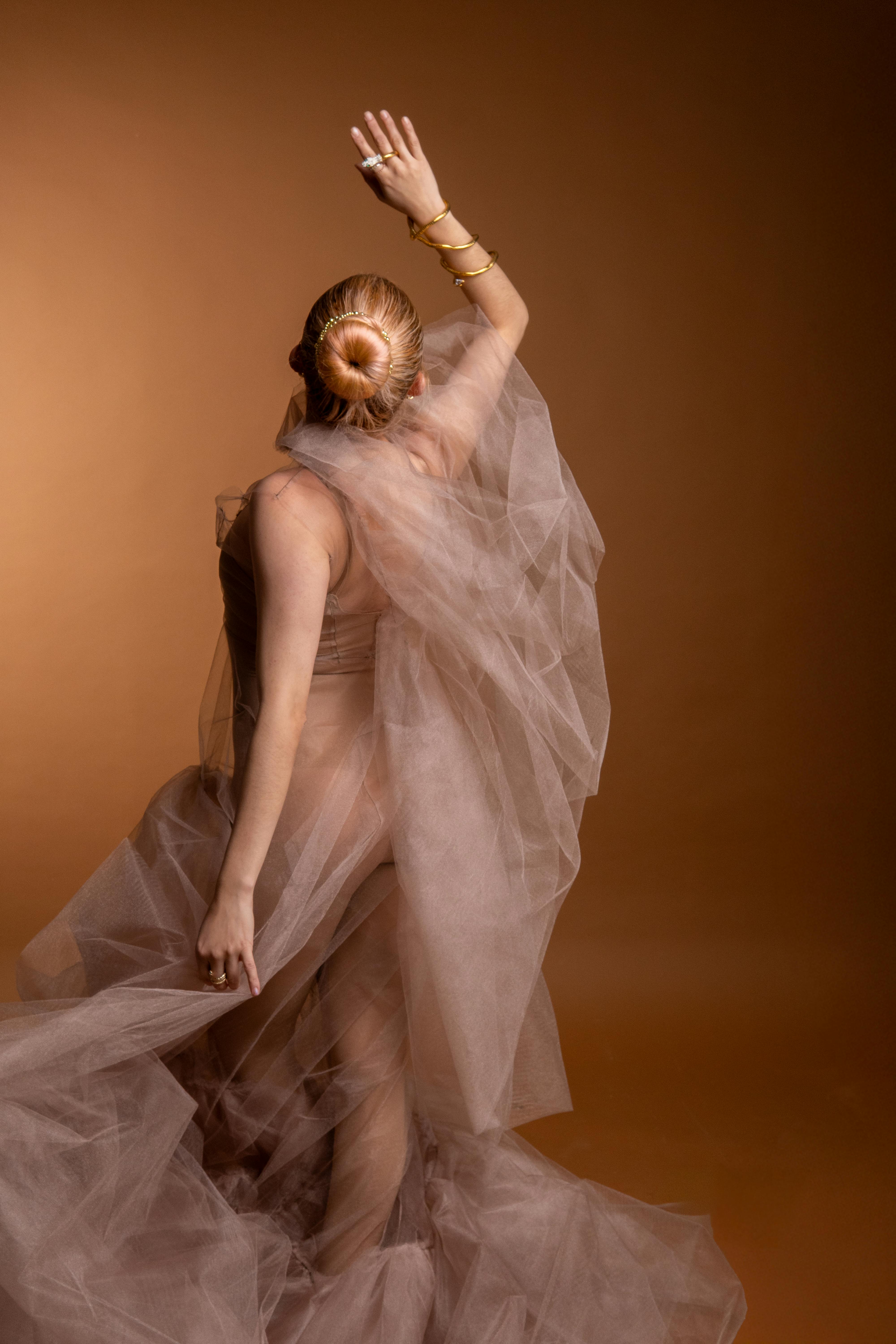 Elegant Ballet Dancer Posing on Mocha Backdrop · Free Stock Photo