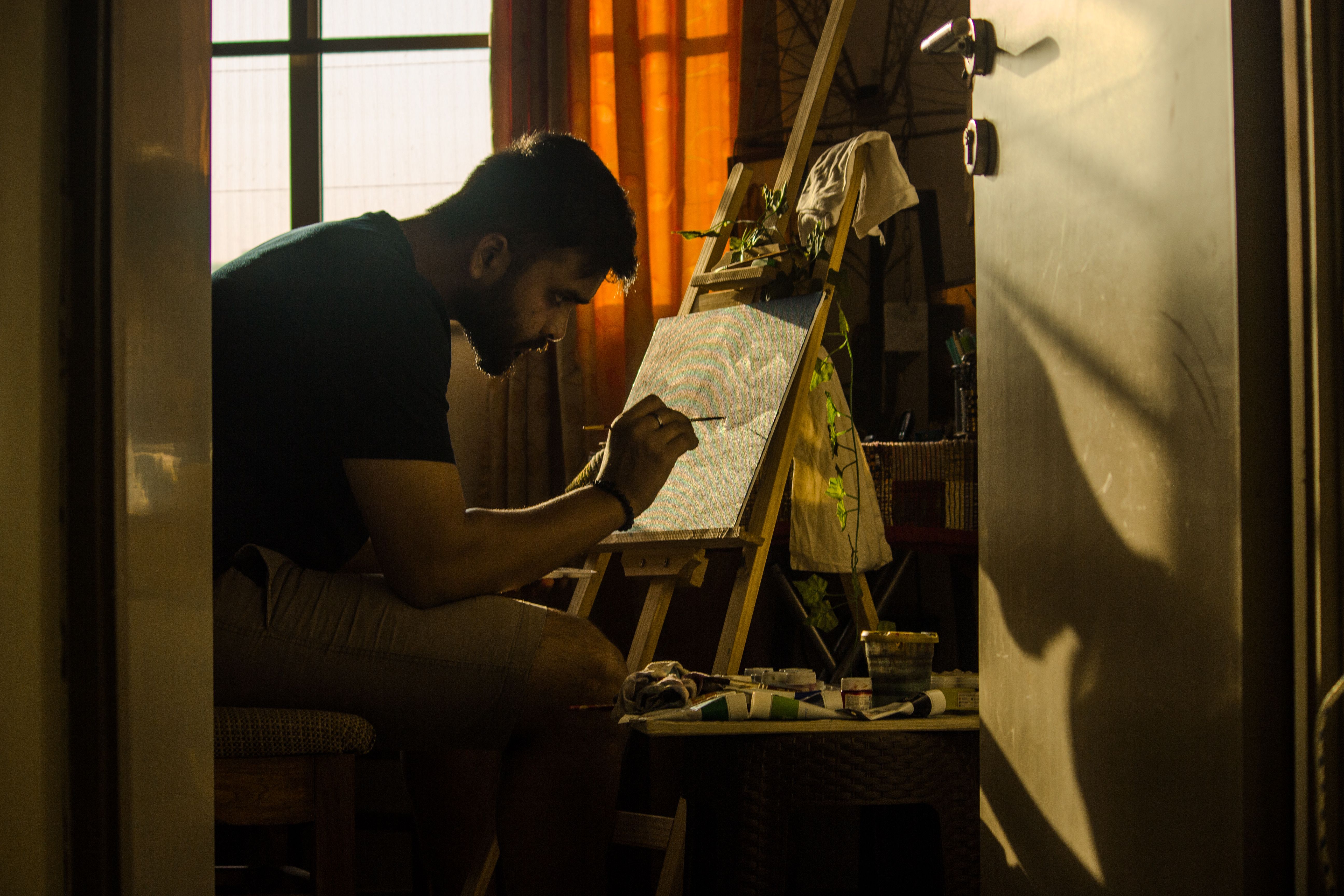 Focused Artist Painting in Sunlit Studio · Free Stock Photo