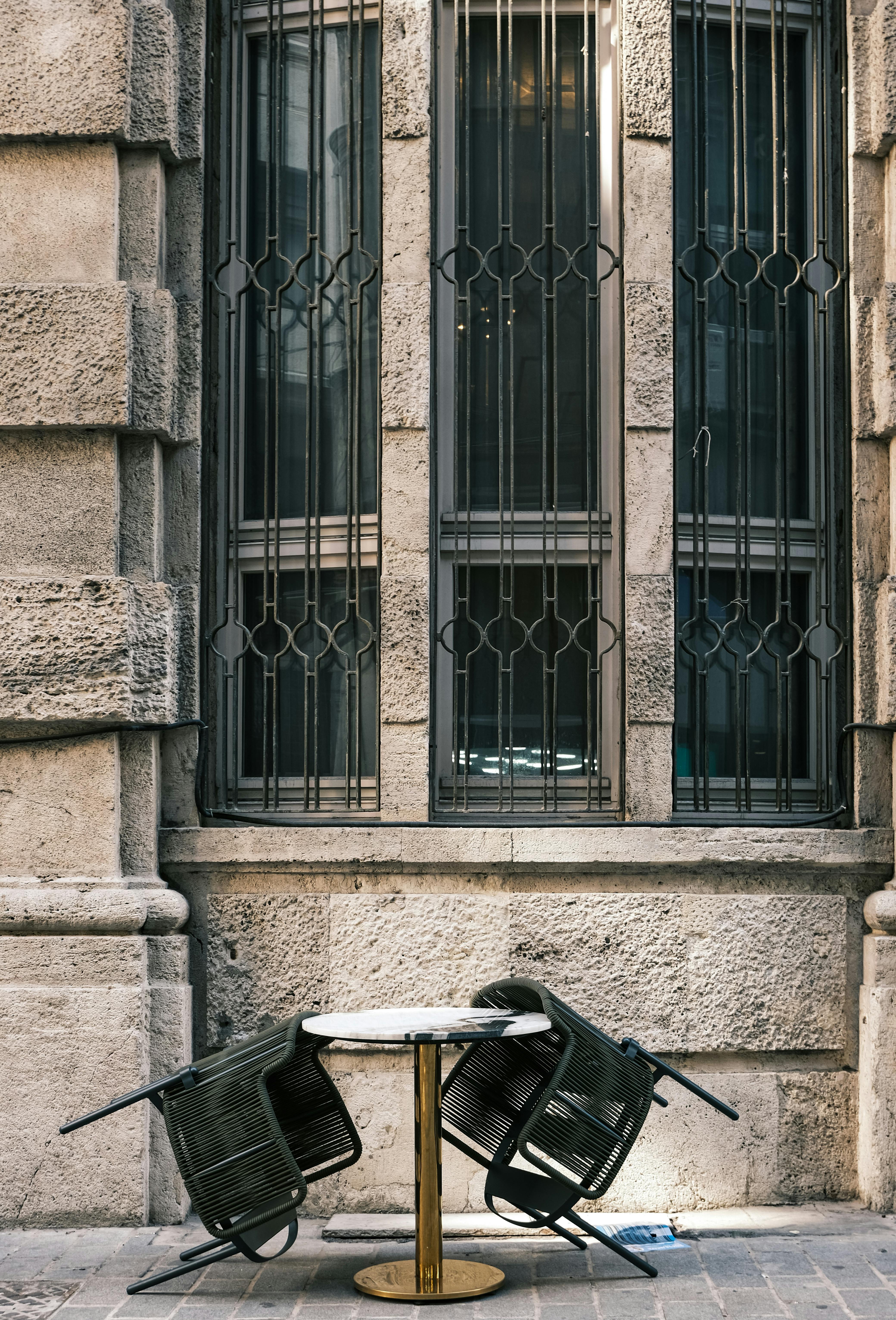 Chairs Tipped Against Stone Wall and Window Outdoors · Free Stock Photo