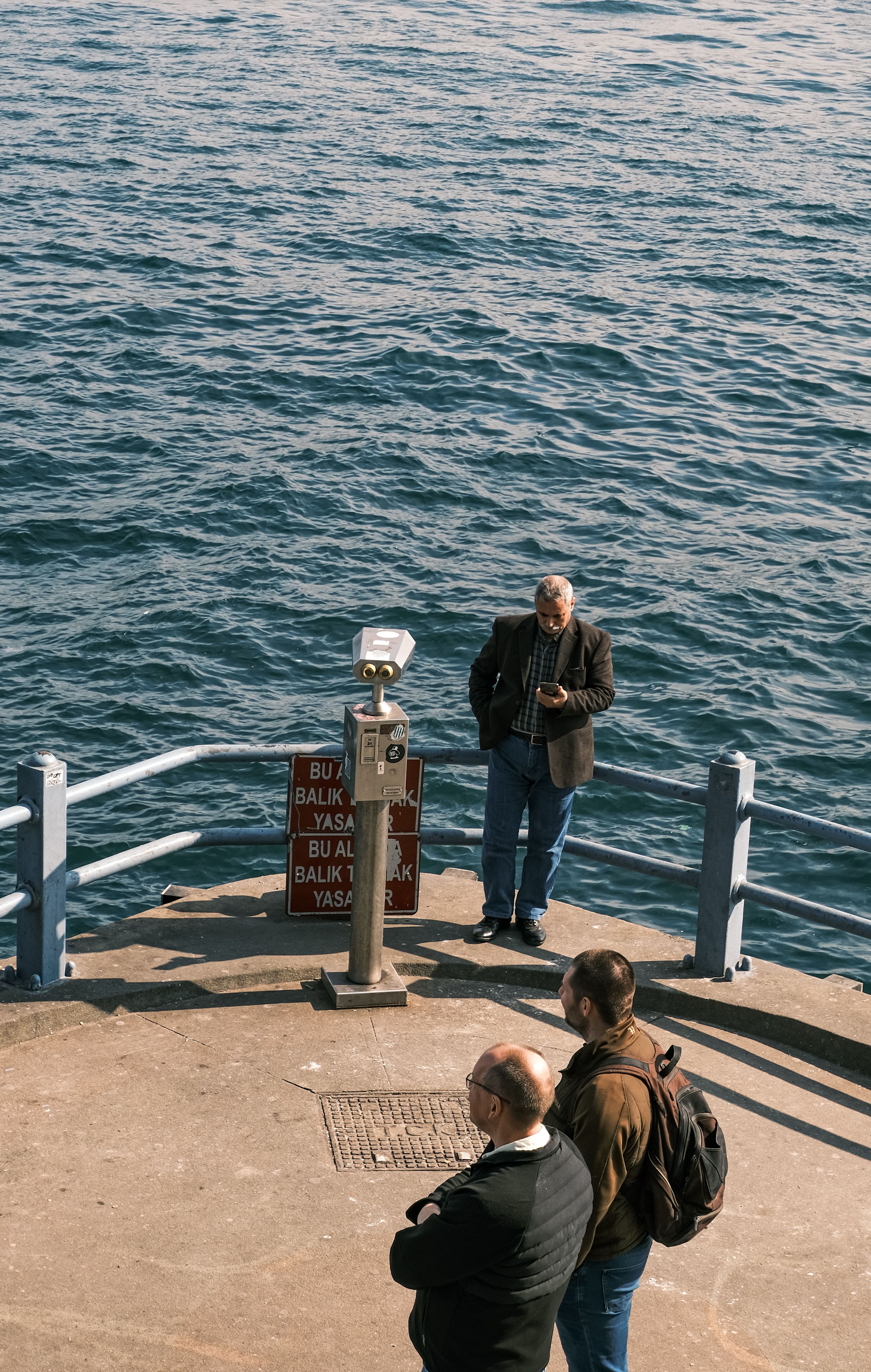 Three Men at Seaside Observation Point · Free Stock Photo