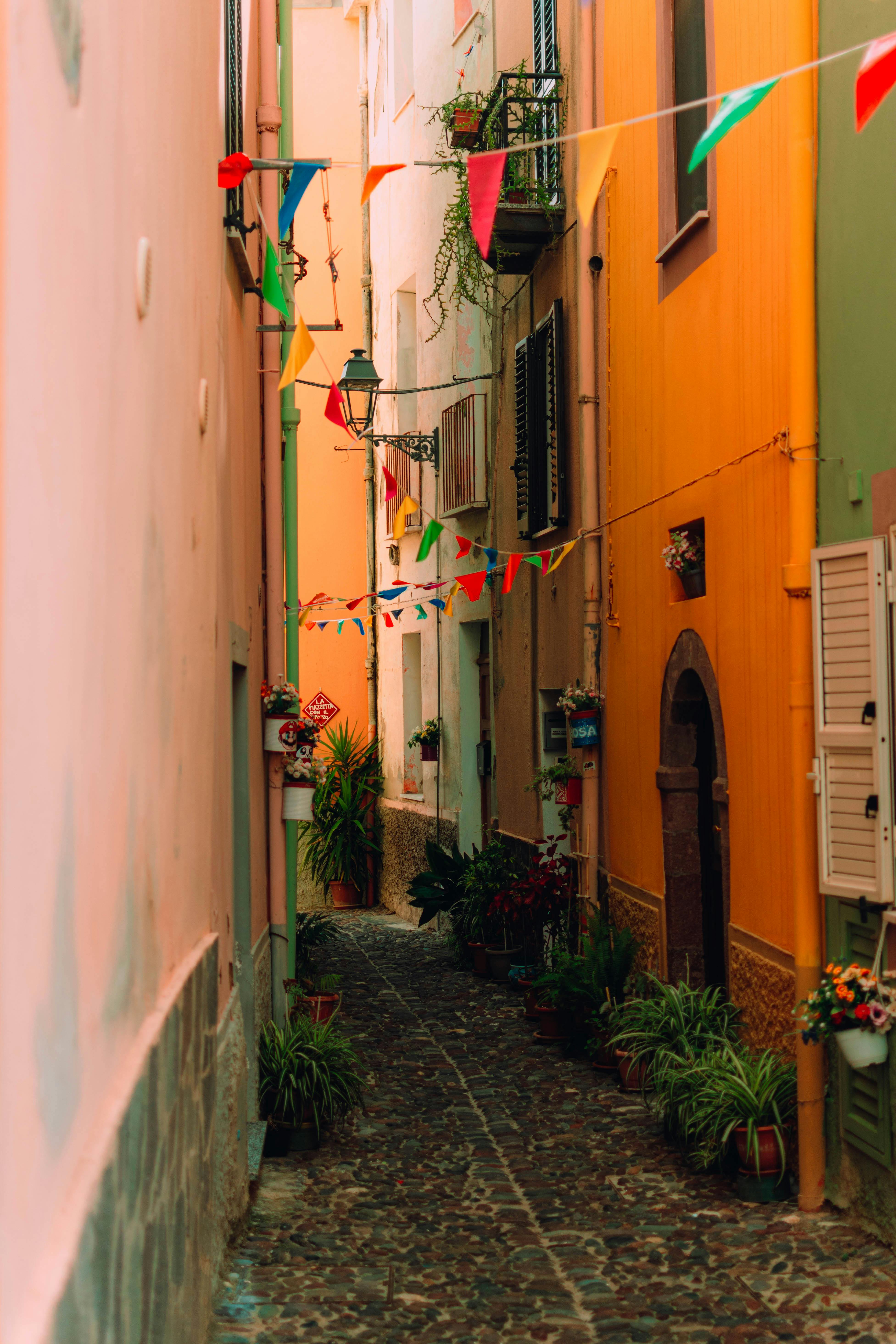 Charming Narrow European Alley with Colorful Flags · Free Stock Photo