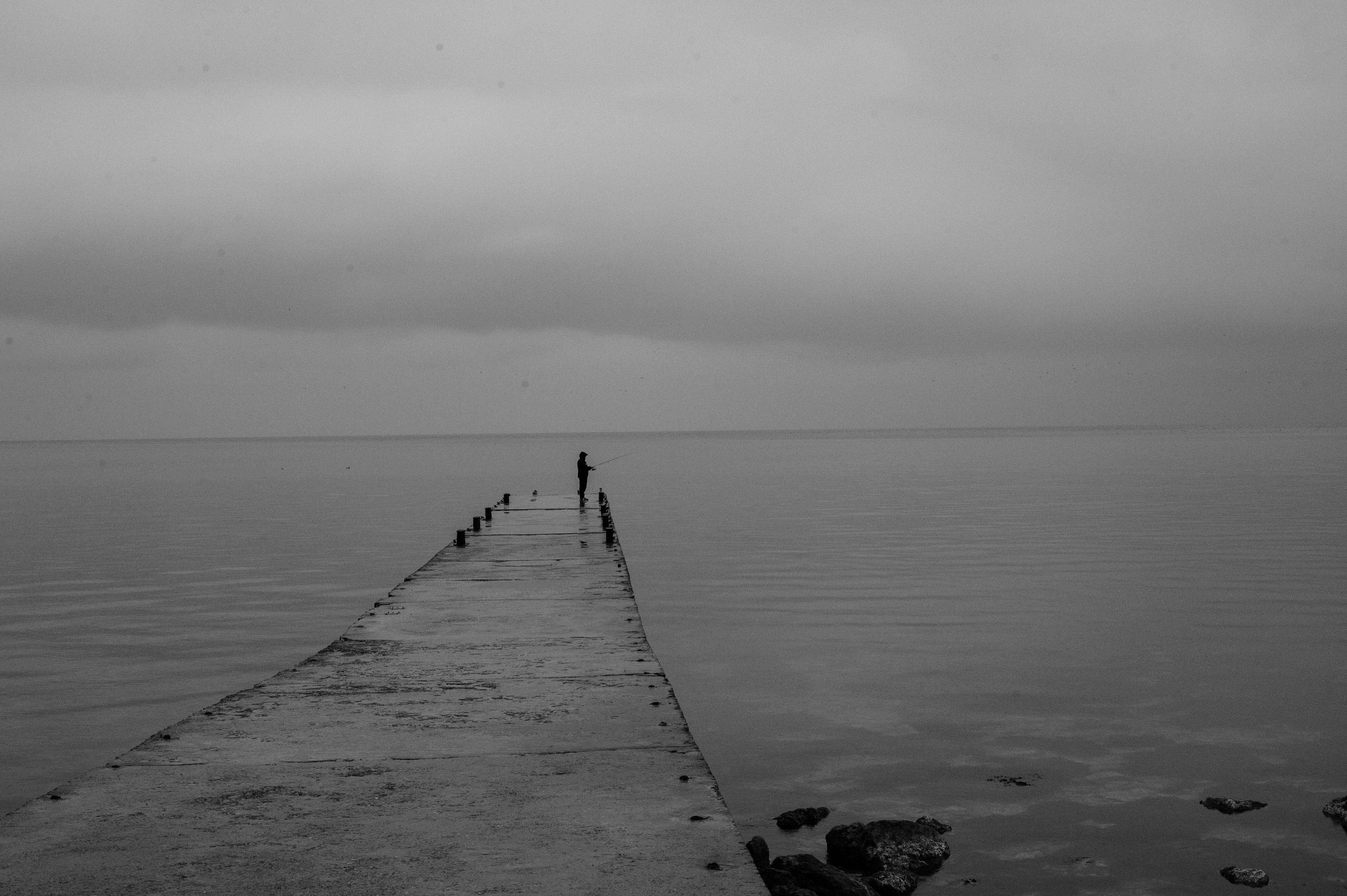 Solitary Figure on a Serene Pier · Free Stock Photo