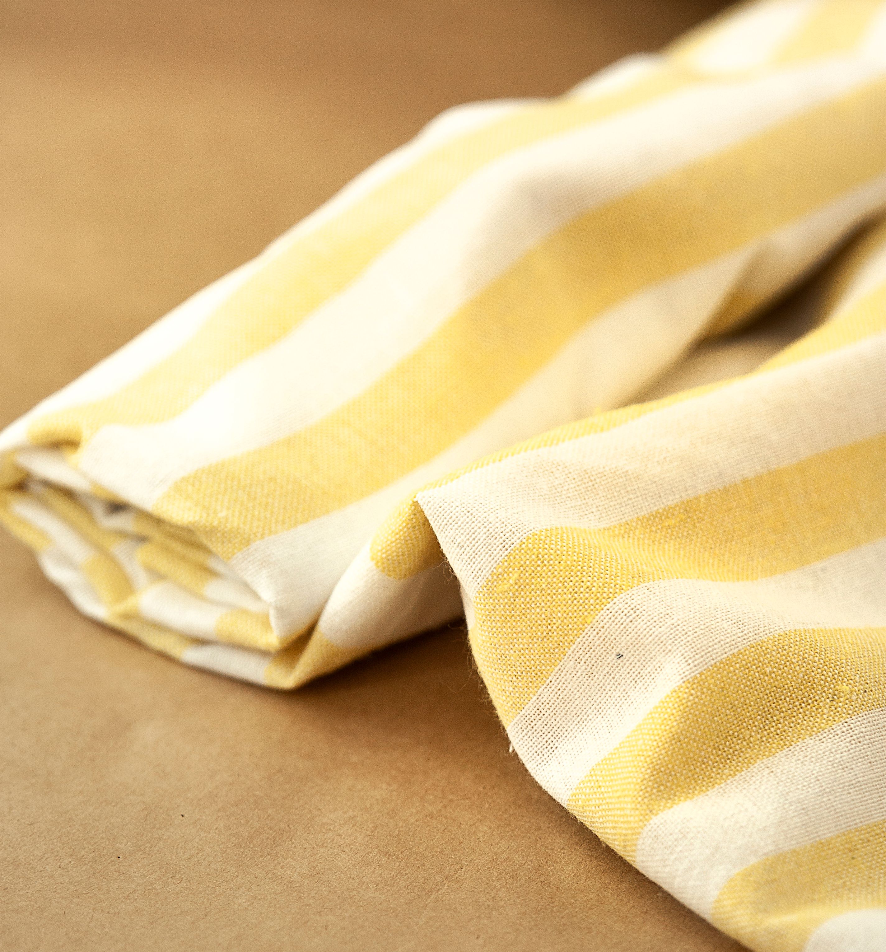Yellow and White Striped Fabric Folded on Table · Free Stock Photo