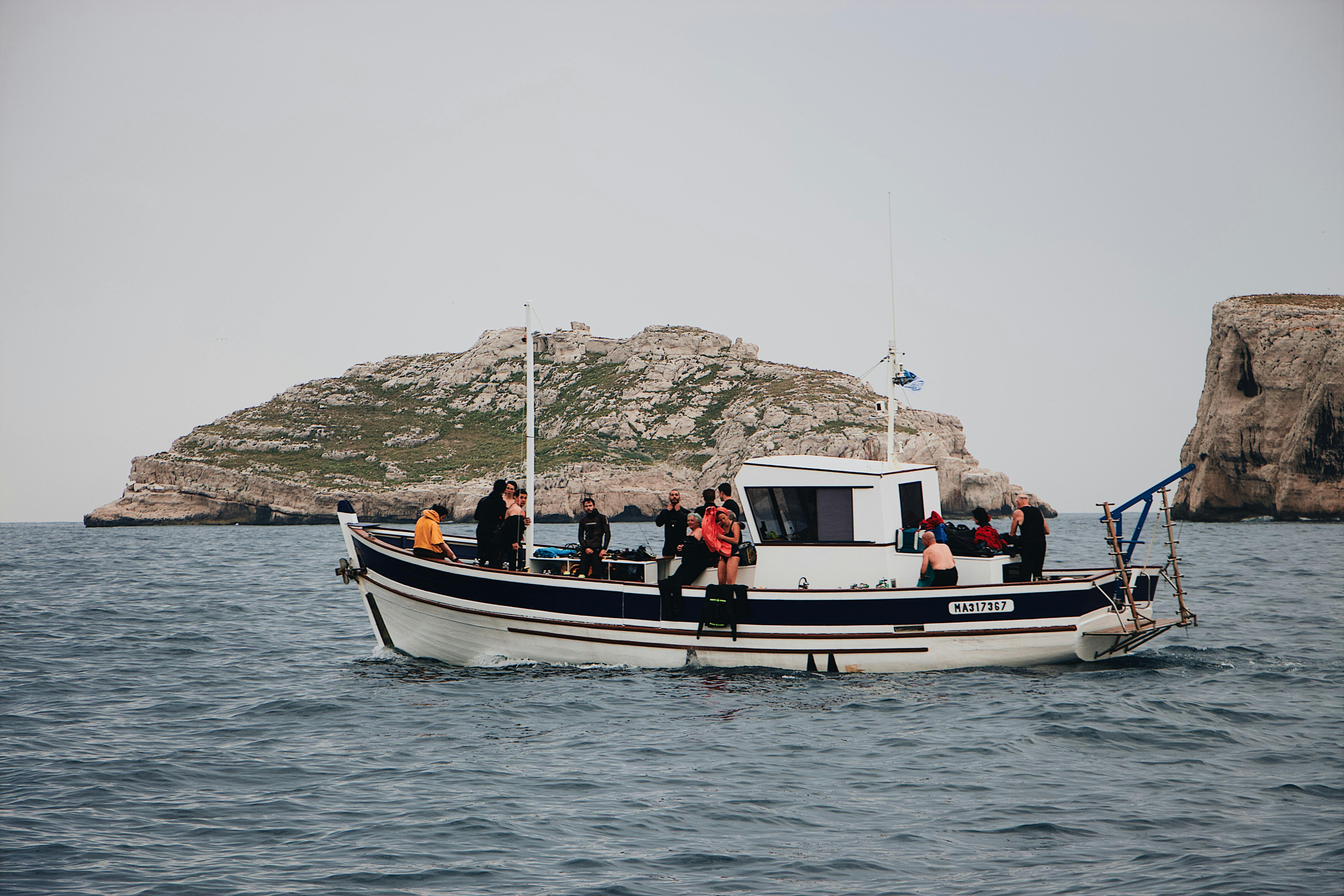 People riding boat near cliffs · Free Stock Photo