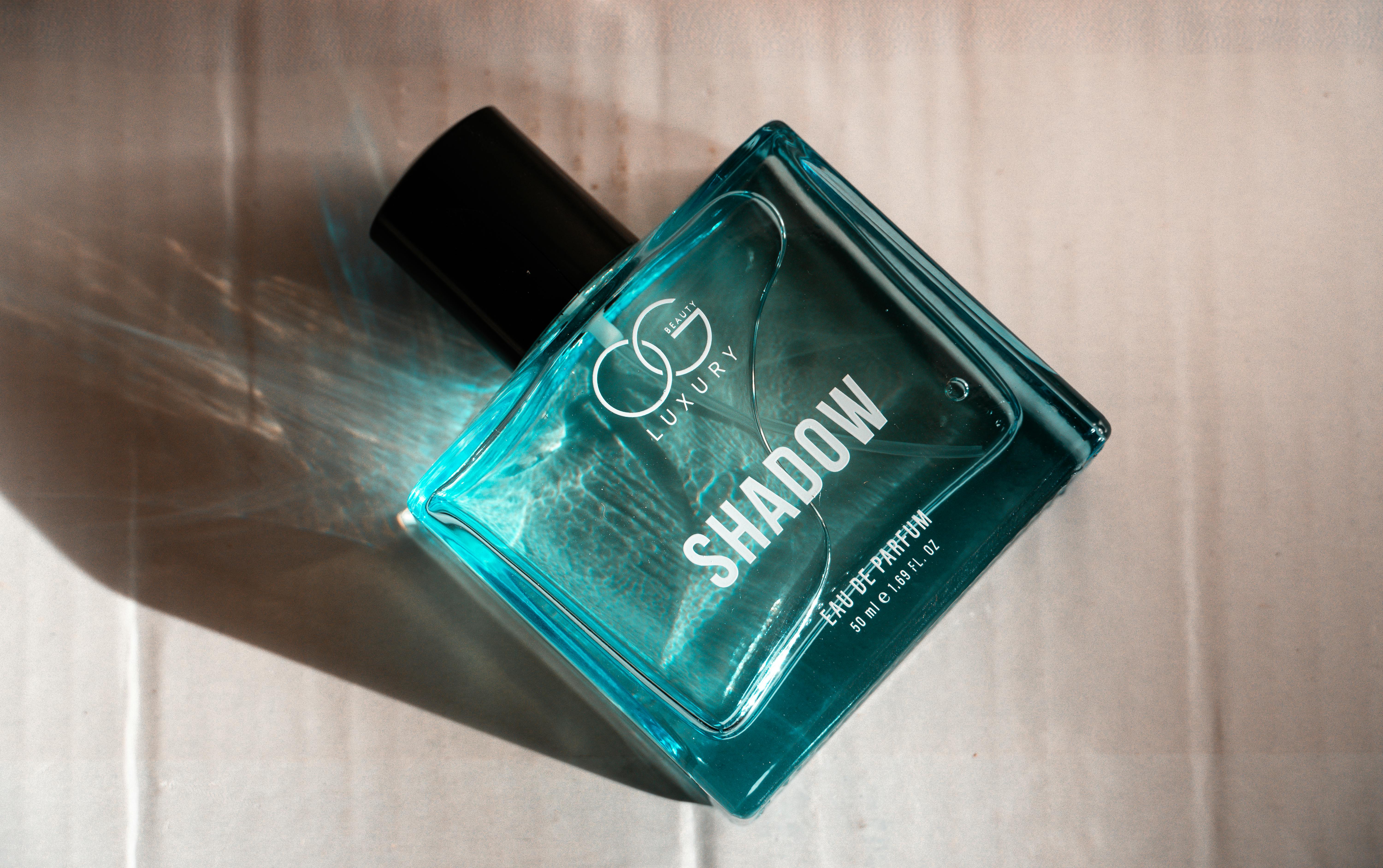 Elegant Shadow Perfume Bottle on Textured Surface · Free Stock Photo