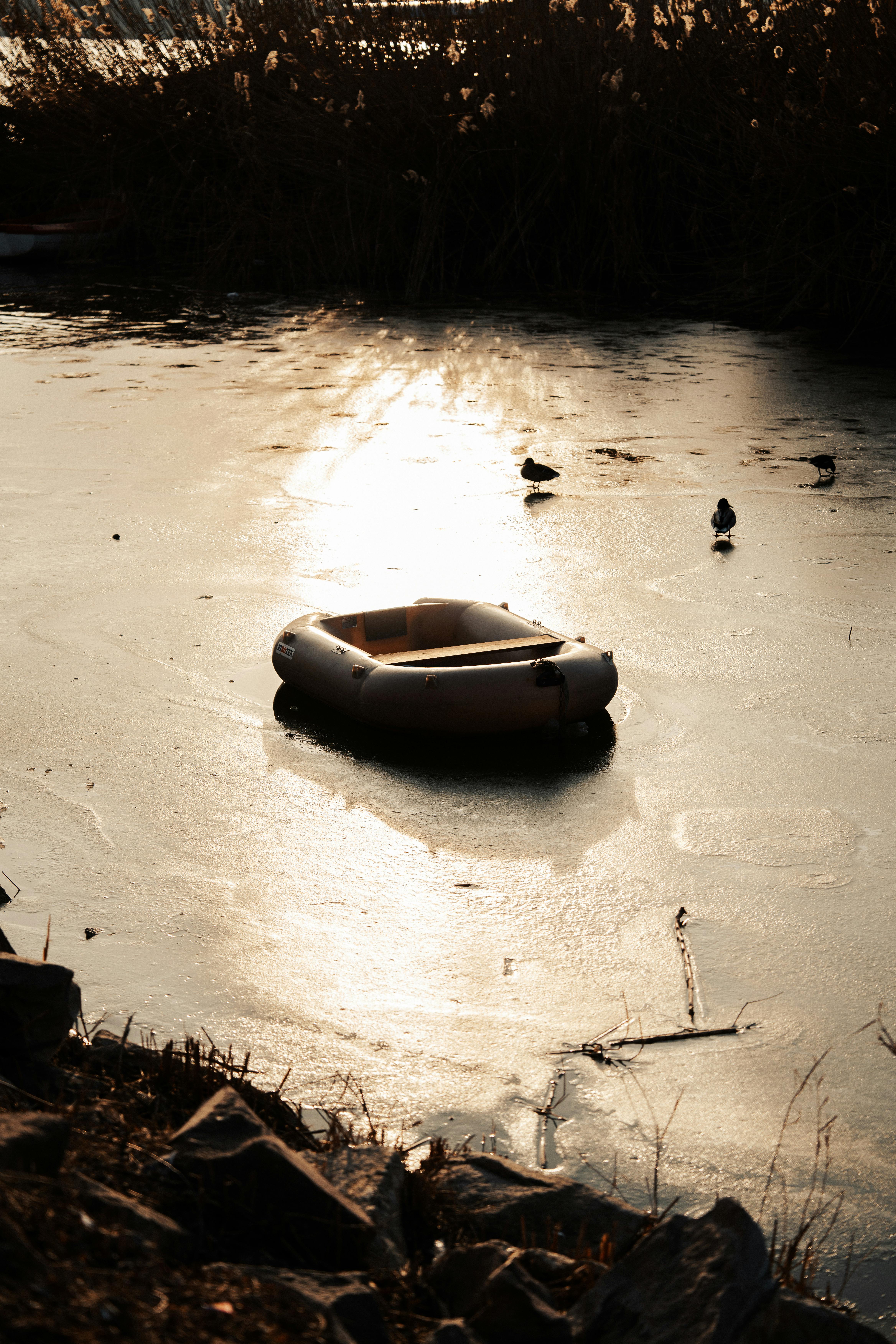 Ice-covered lake with abandoned inflatable boat · Free Stock Photo