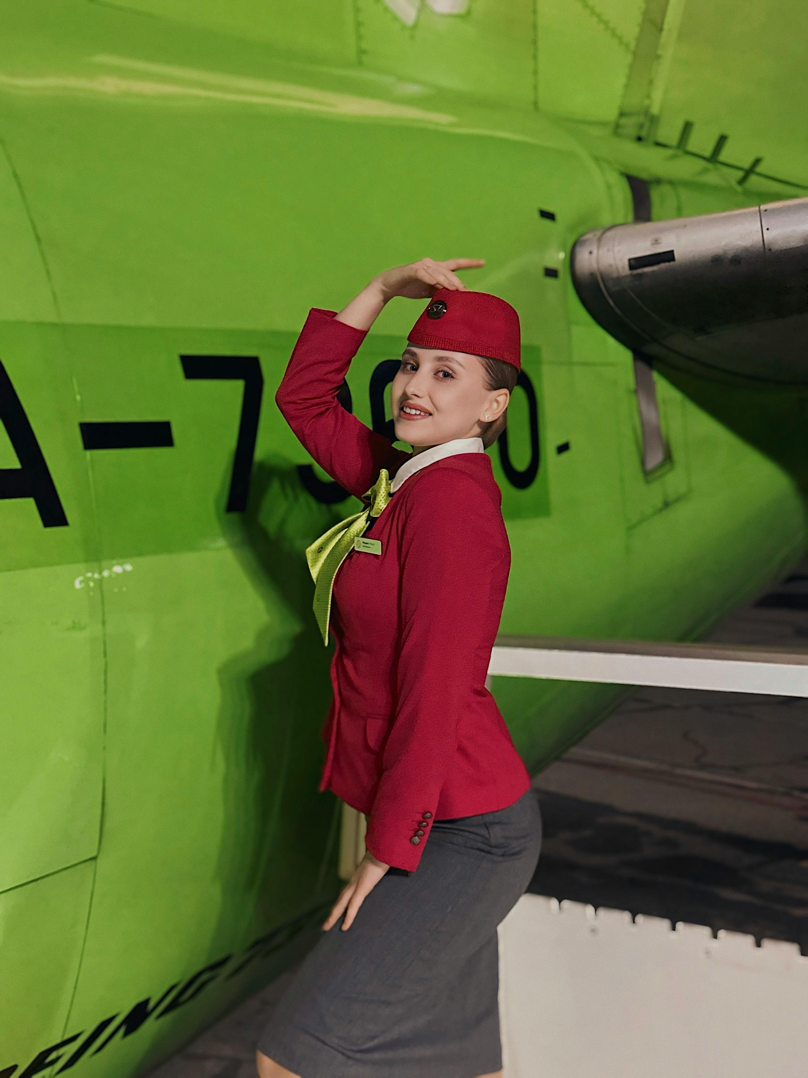 Flight Attendant Posing by Green Aircraft · Free Stock Photo