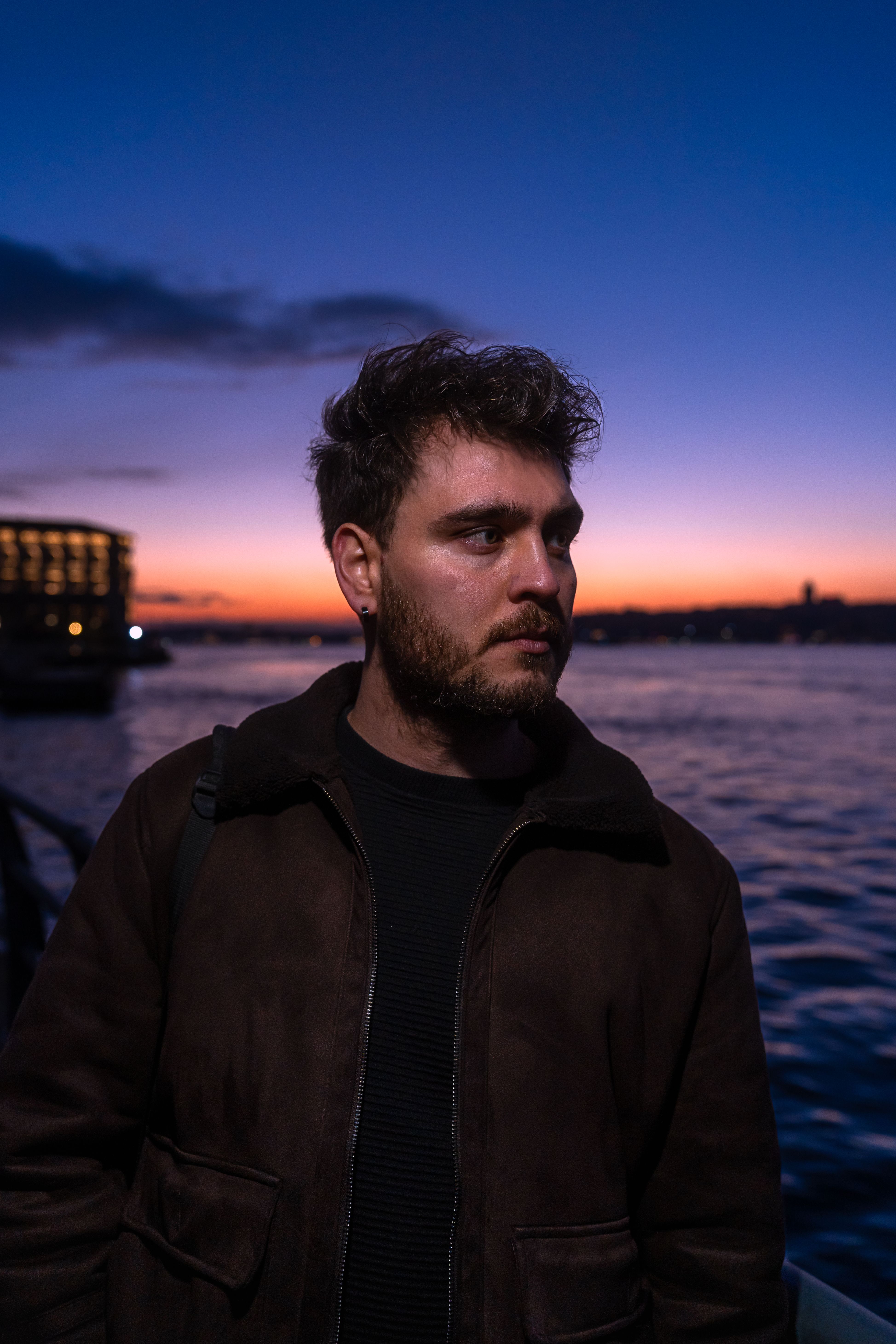 Young Man at Waterfront During Vibrant Twilight · Free Stock Photo