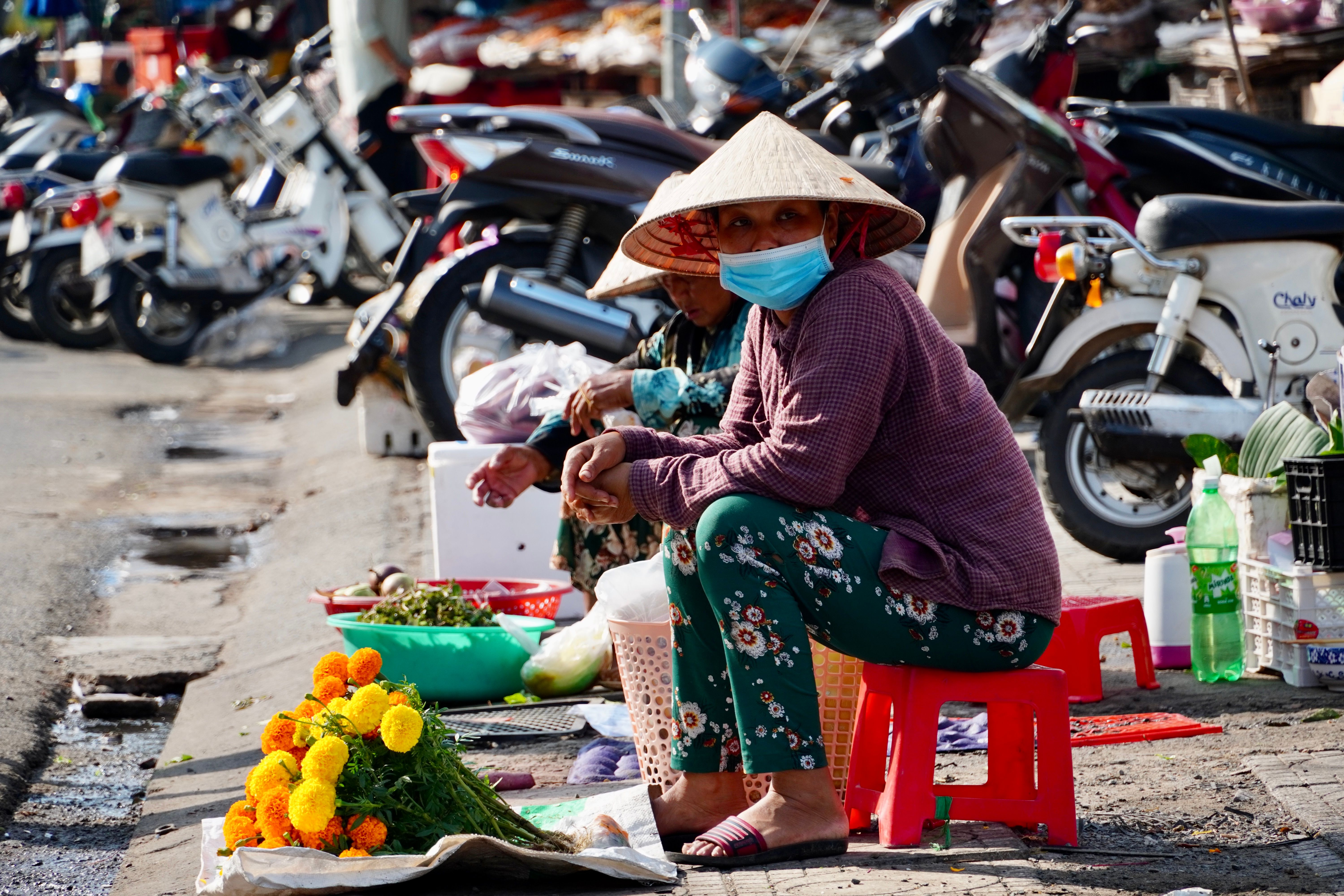 Asian Market Vendor with Traditional Hat and Flowers · Free Stock Photo