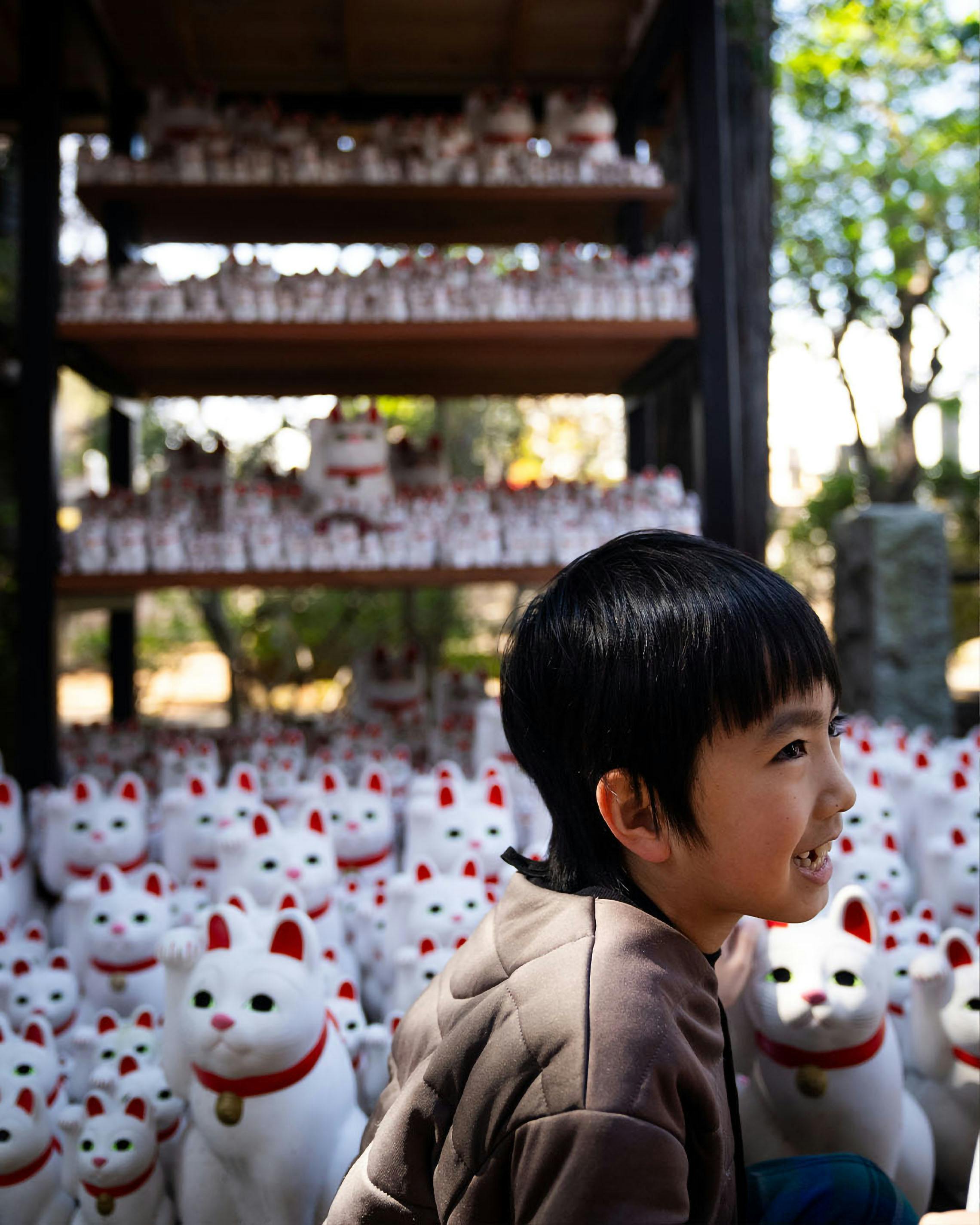Child at Gotokuji Temple with Maneki-neko Figurines · Free Stock Photo