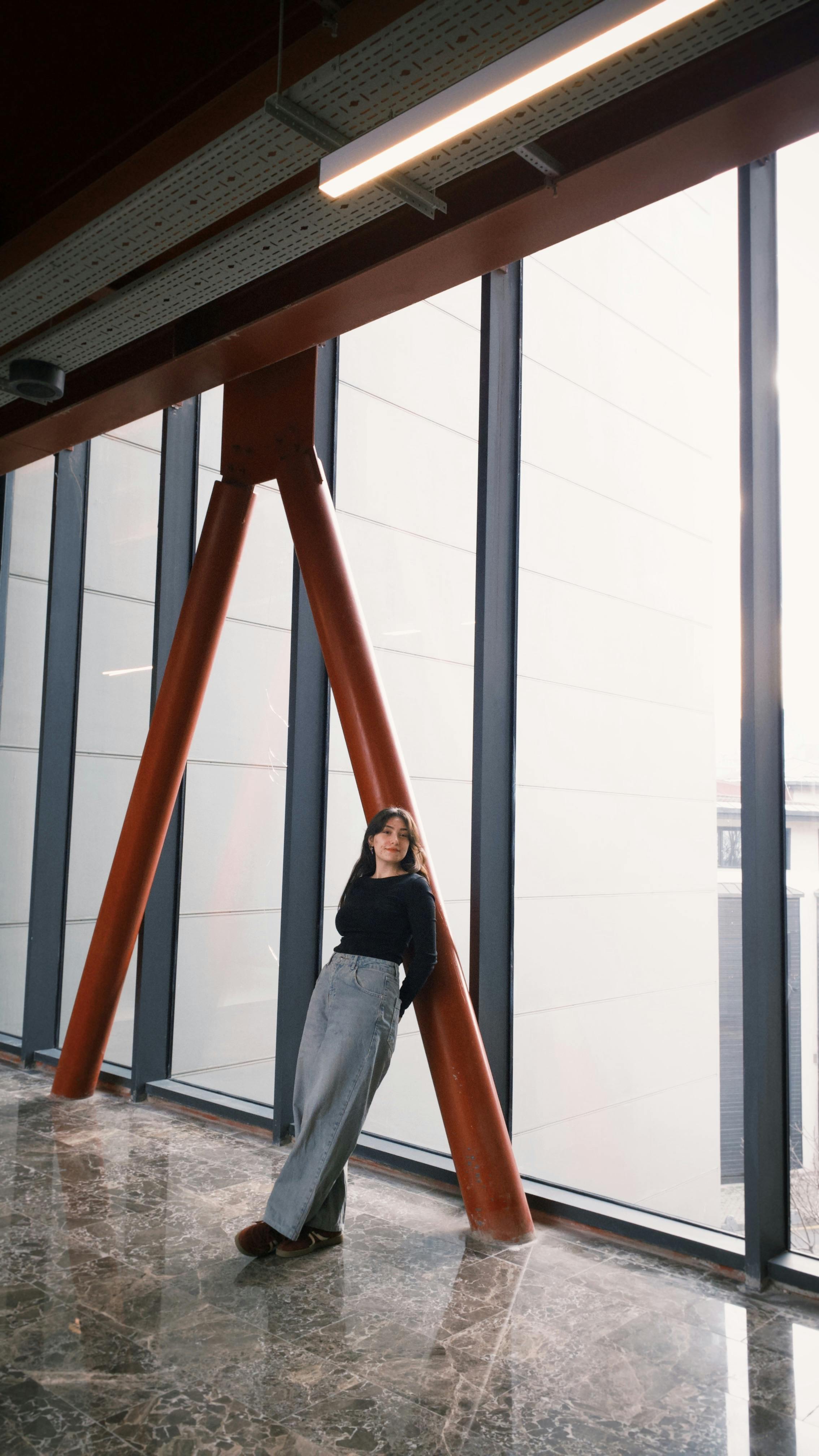 Woman Leaning Against Modern Architectural Structure · Free Stock Photo