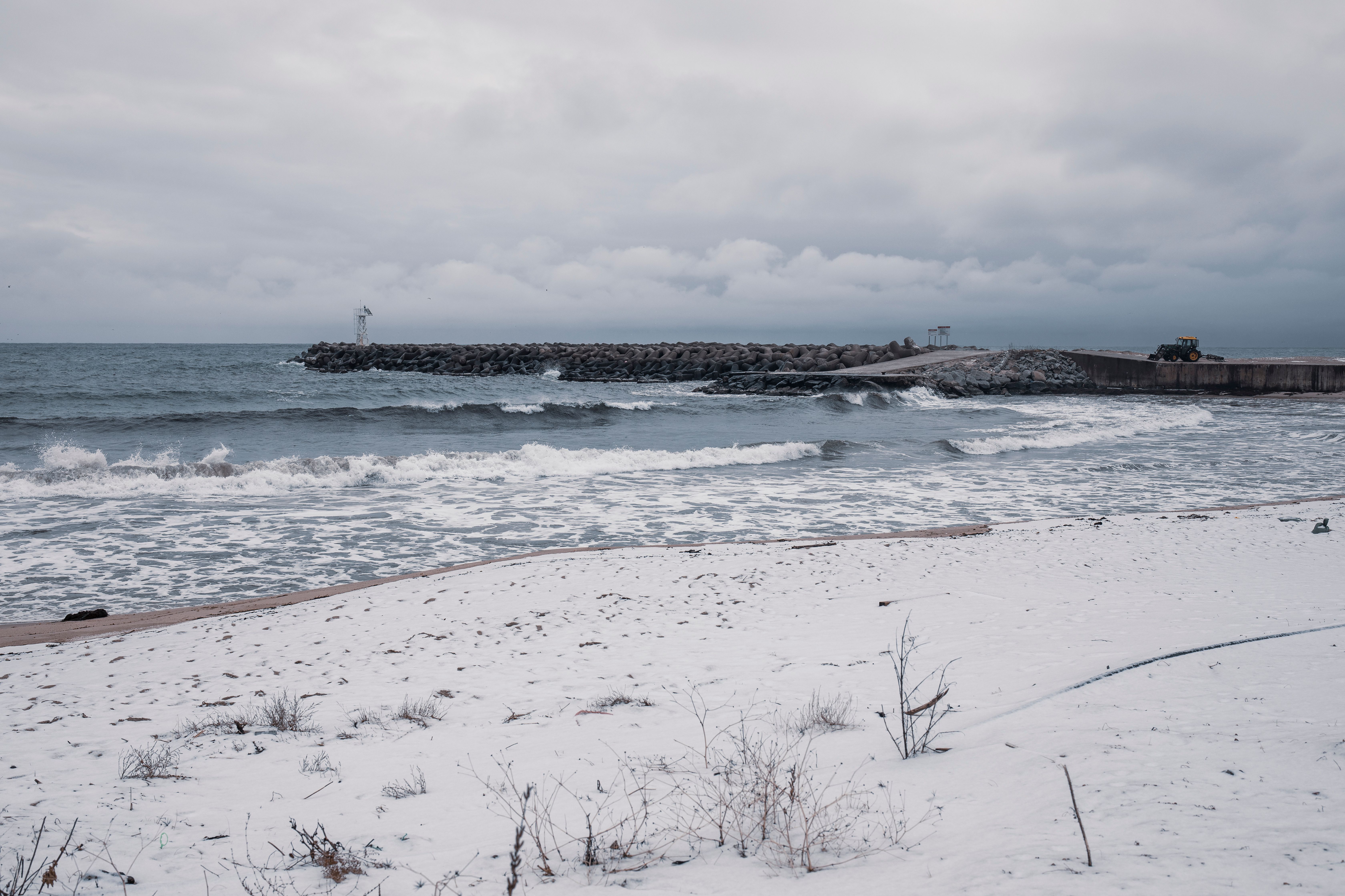 Snowy Beach Scene with Waves and Breakwater · Free Stock Photo