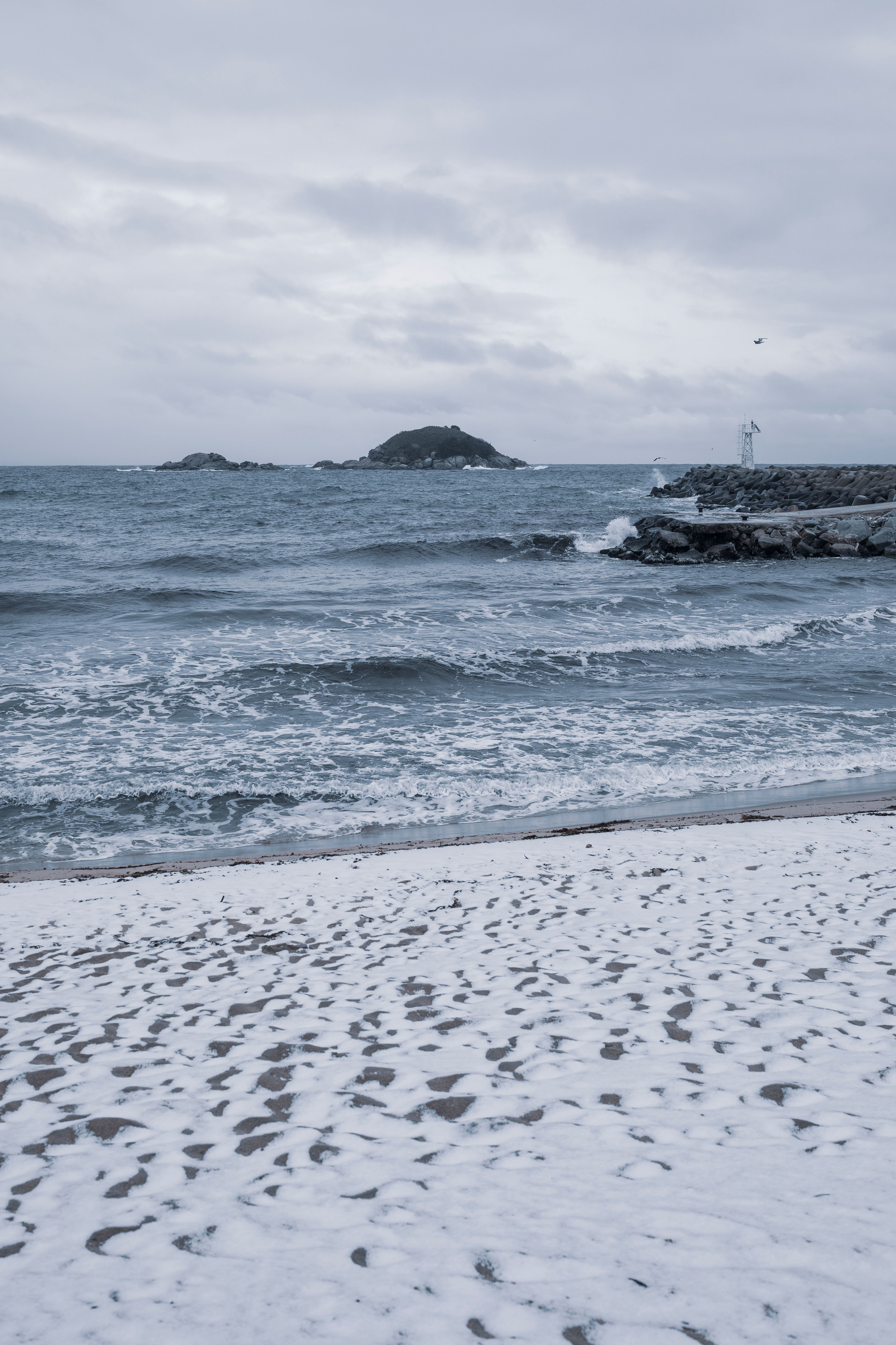Snowy Beach with Overcast Sky and Distant Island · Free Stock Photo