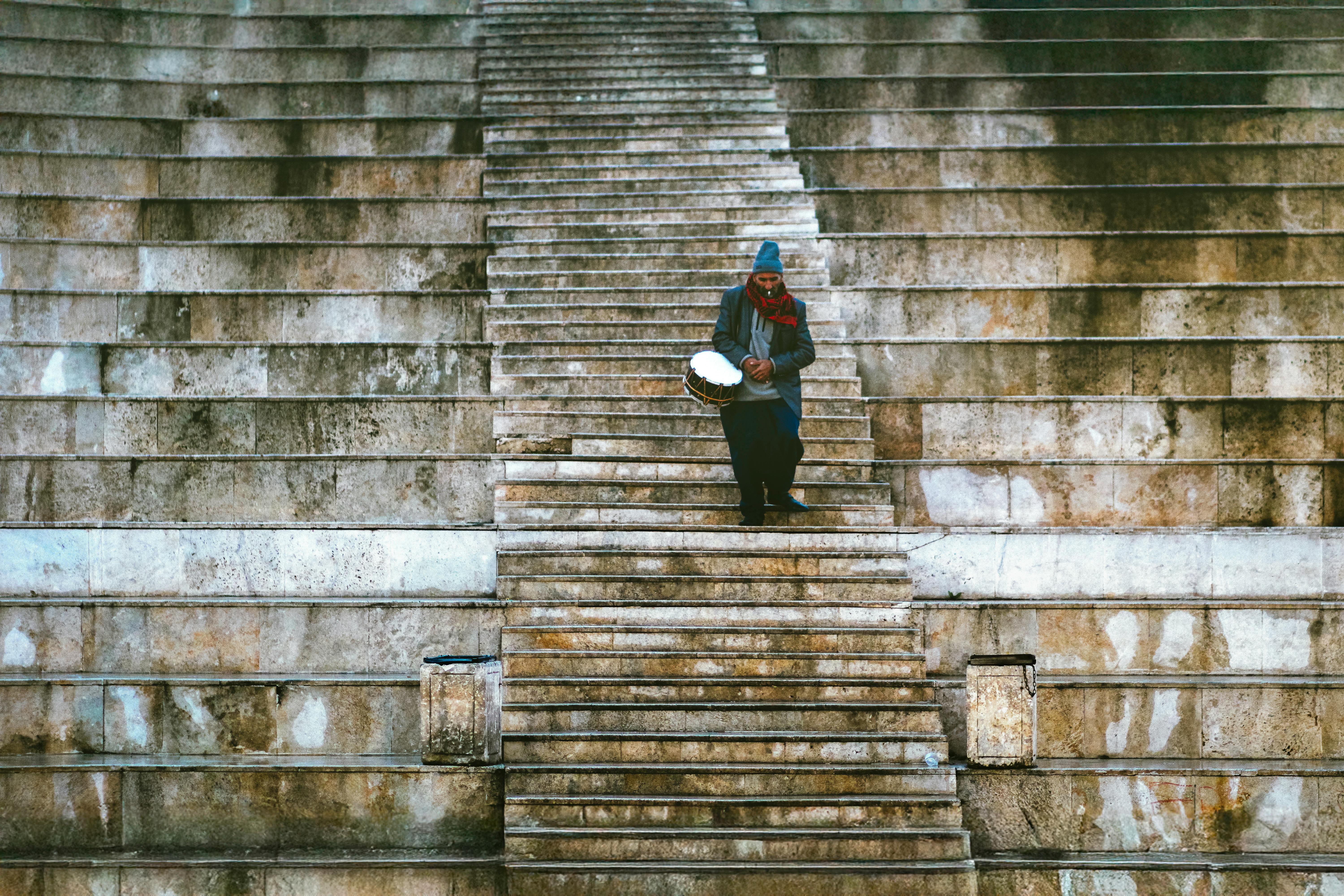 Man Descending Stone Steps with Drum · Free Stock Photo