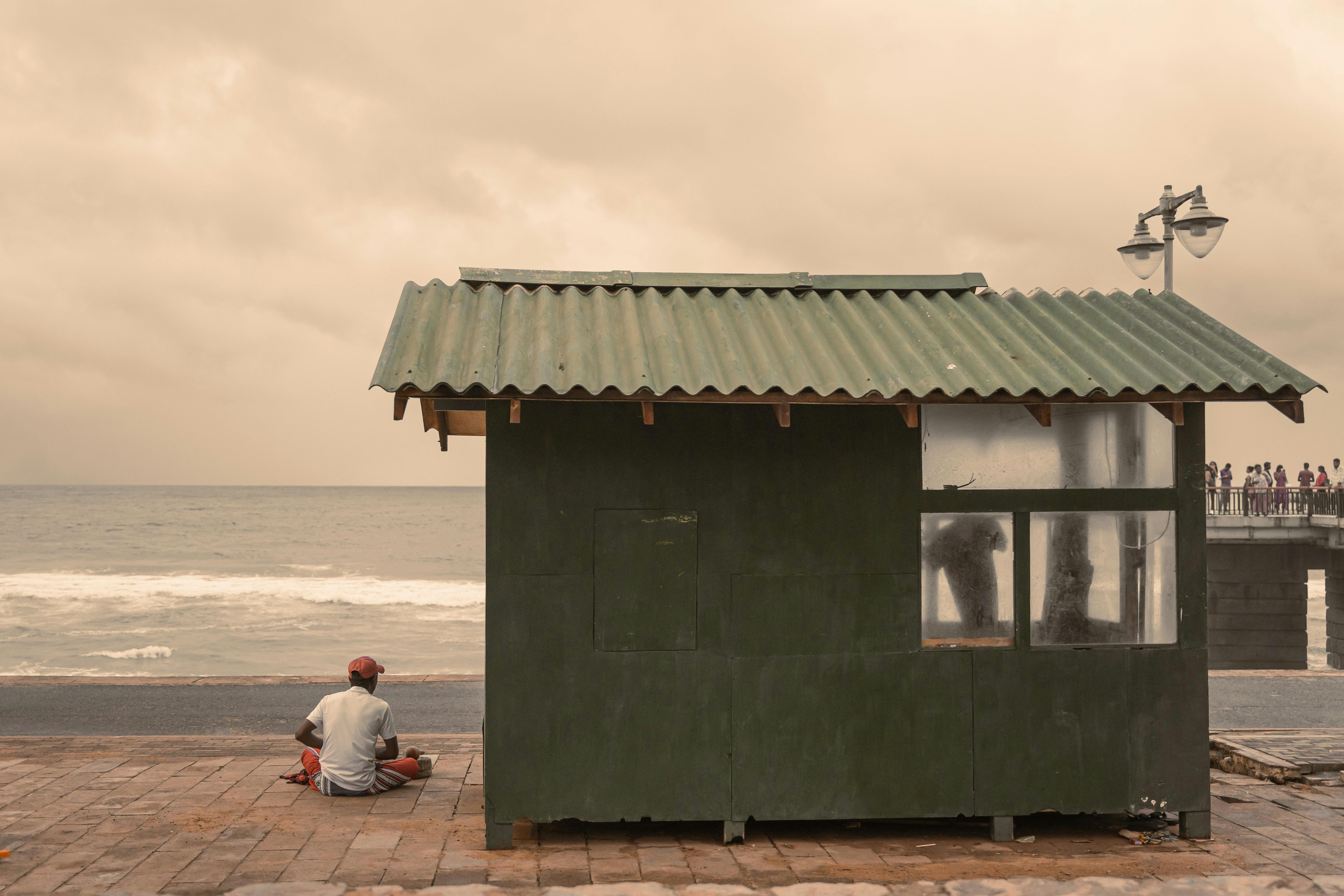Solitary Figure by Oceanfront Green Shack · Free Stock Photo
