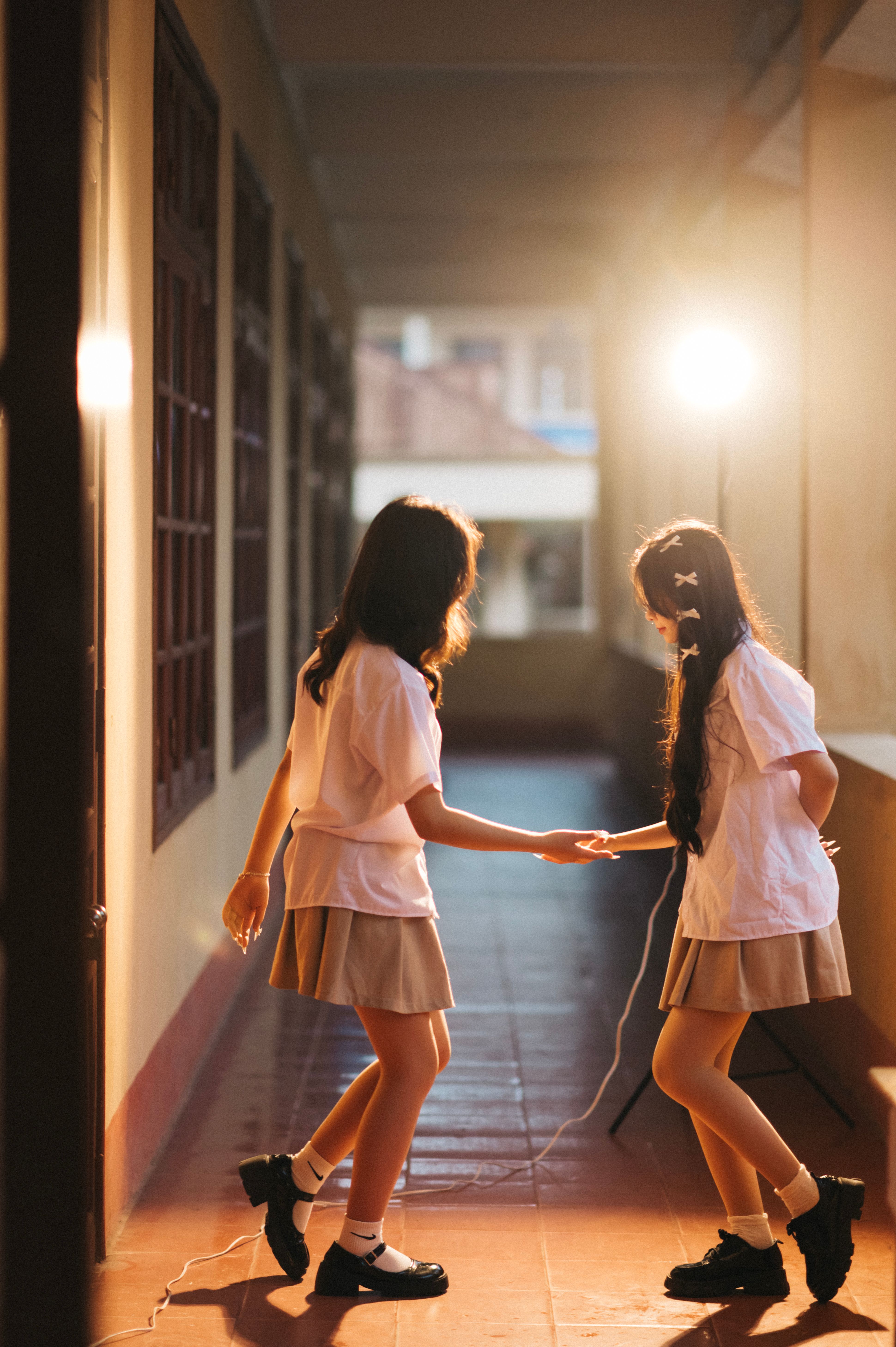 Two girls playing in a sunlit school corridor · Free Stock Photo