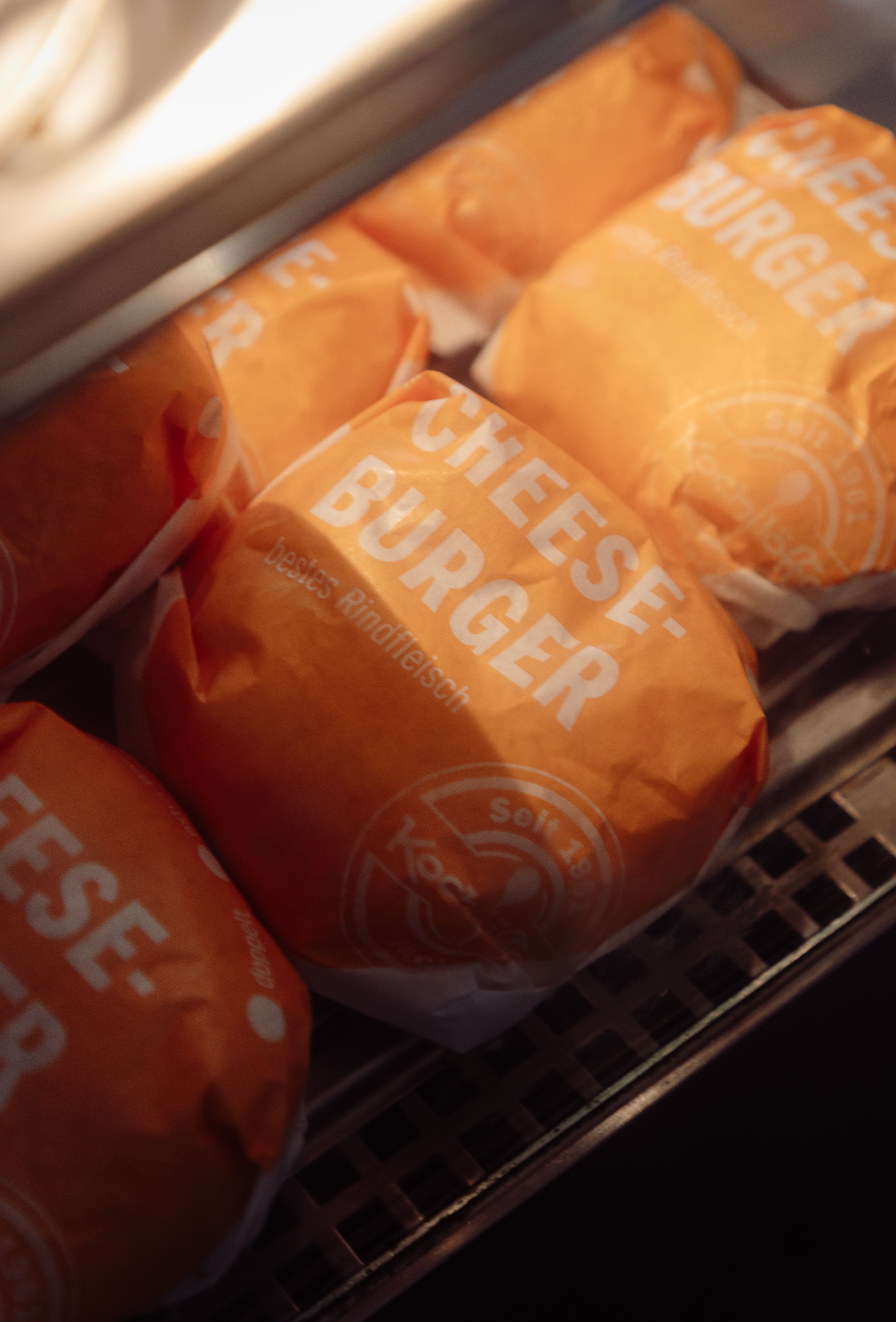 Delicious Cheeseburgers Wrapped in Orange Paper · Free Stock Photo