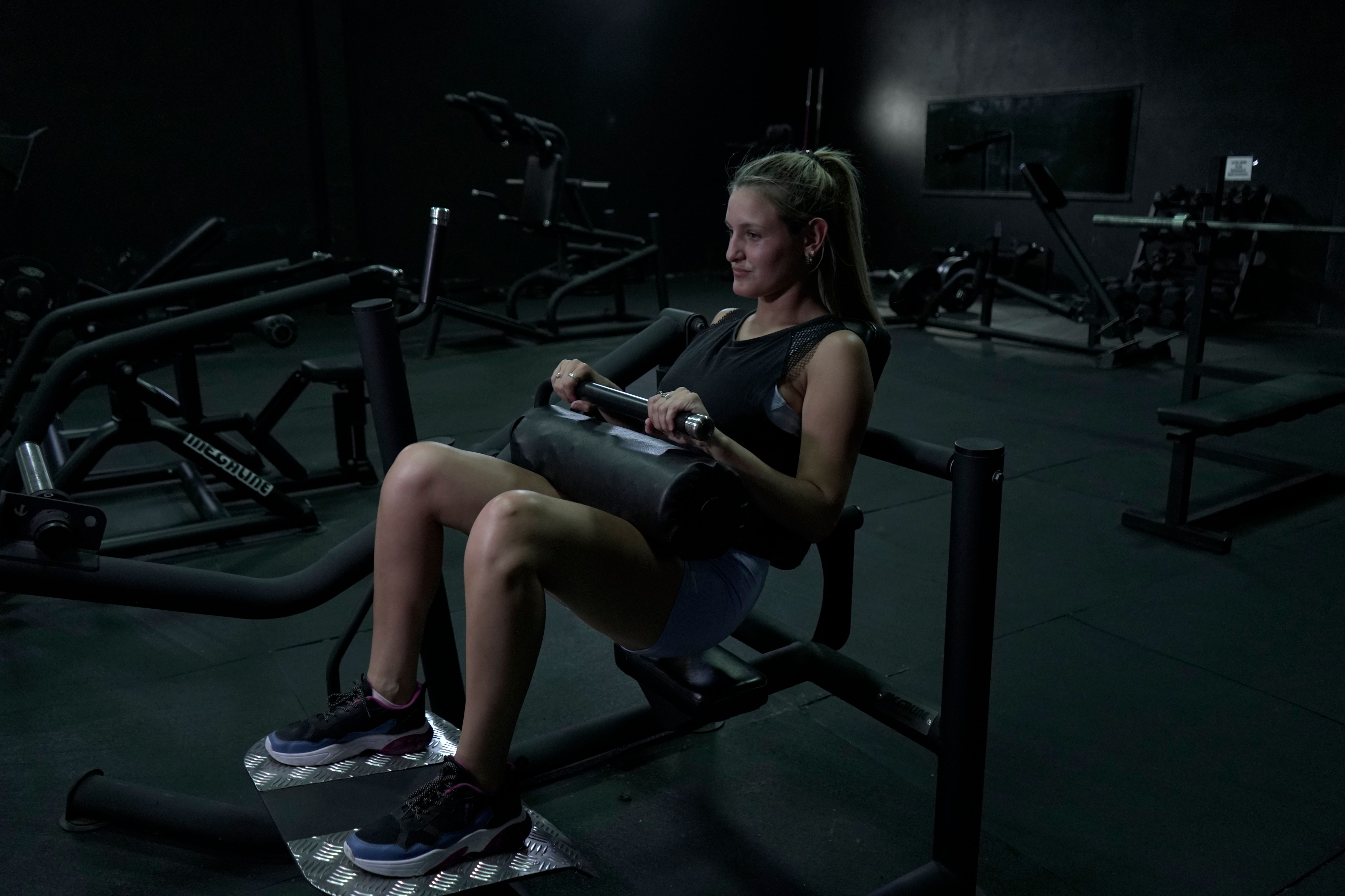 Focused Woman Exercising in a Dark Gym Setting · Free Stock Photo