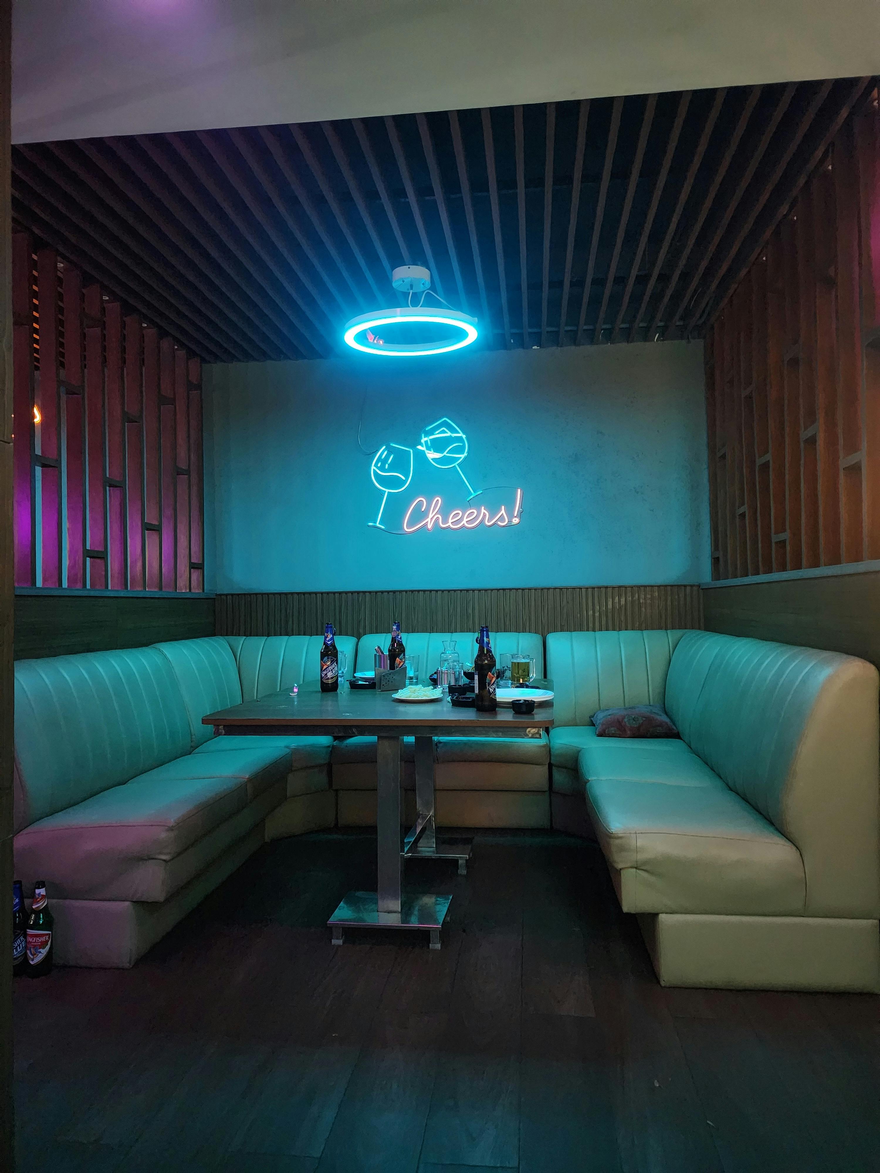 Cozy Lounge Booth with Neon Cheers Sign · Free Stock Photo