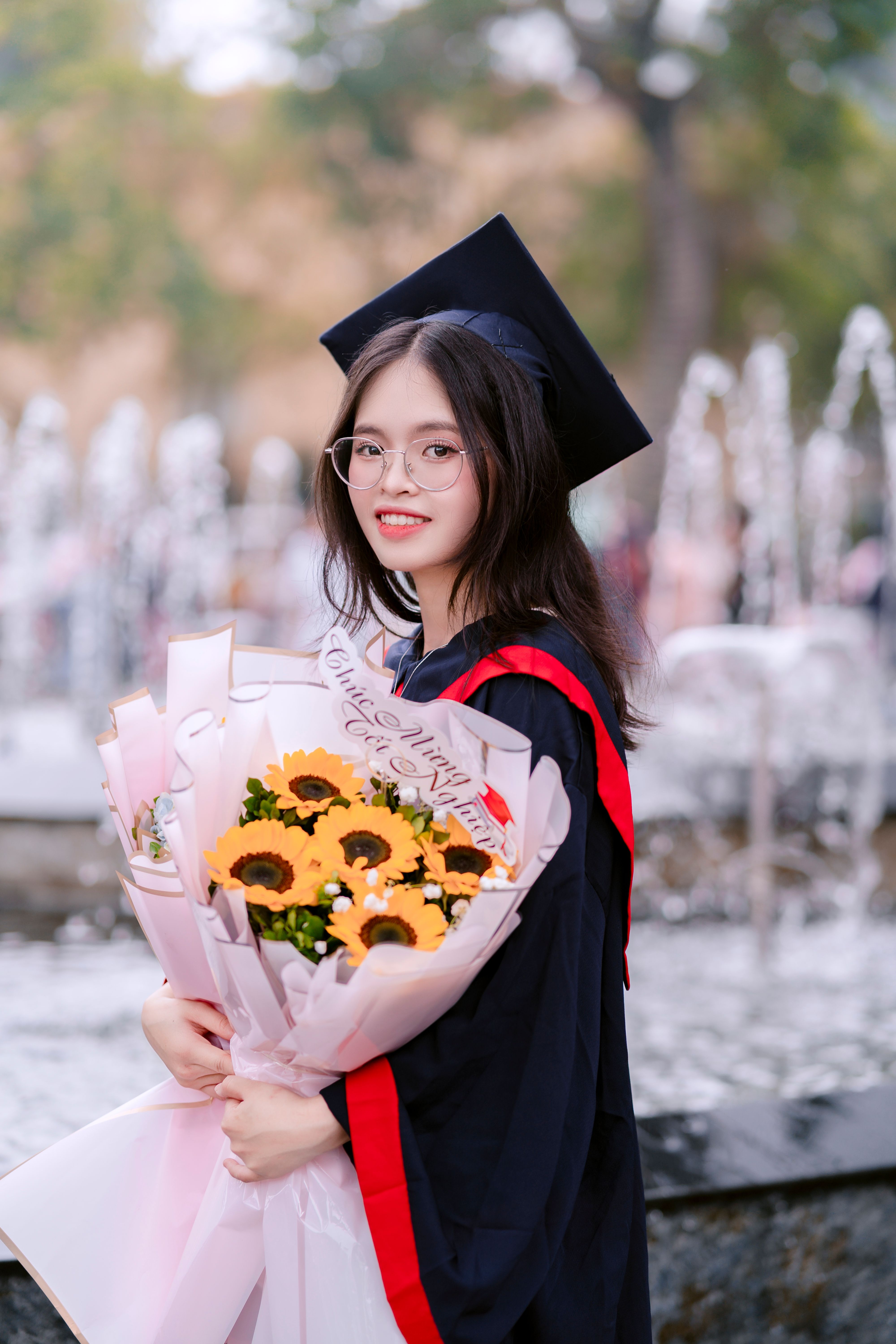 Young Graduate with Sunflower Bouquet Celebrating · Free Stock Photo