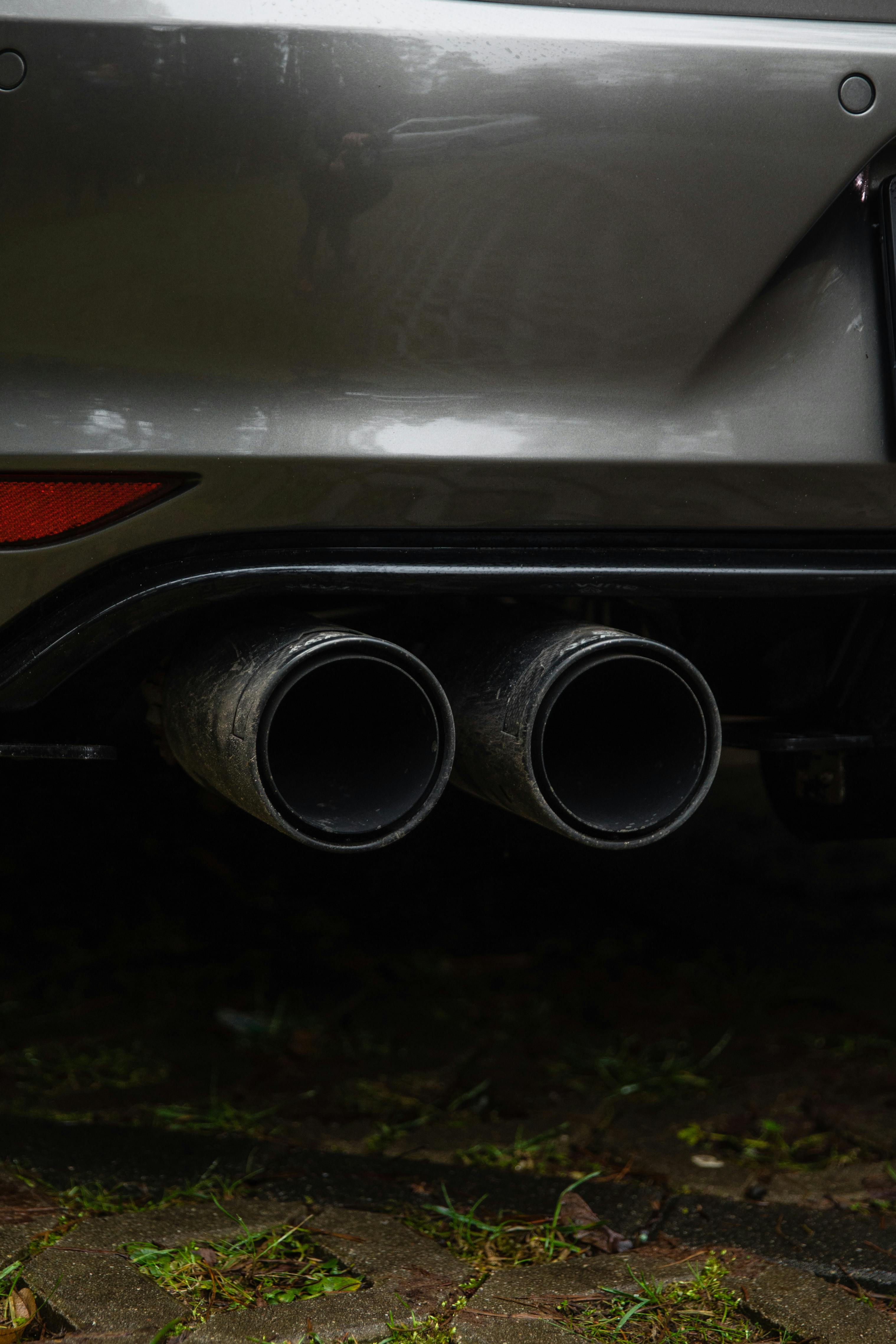 Close-up of Dual Car Exhaust Pipes in Parking Lot · Free Stock Photo