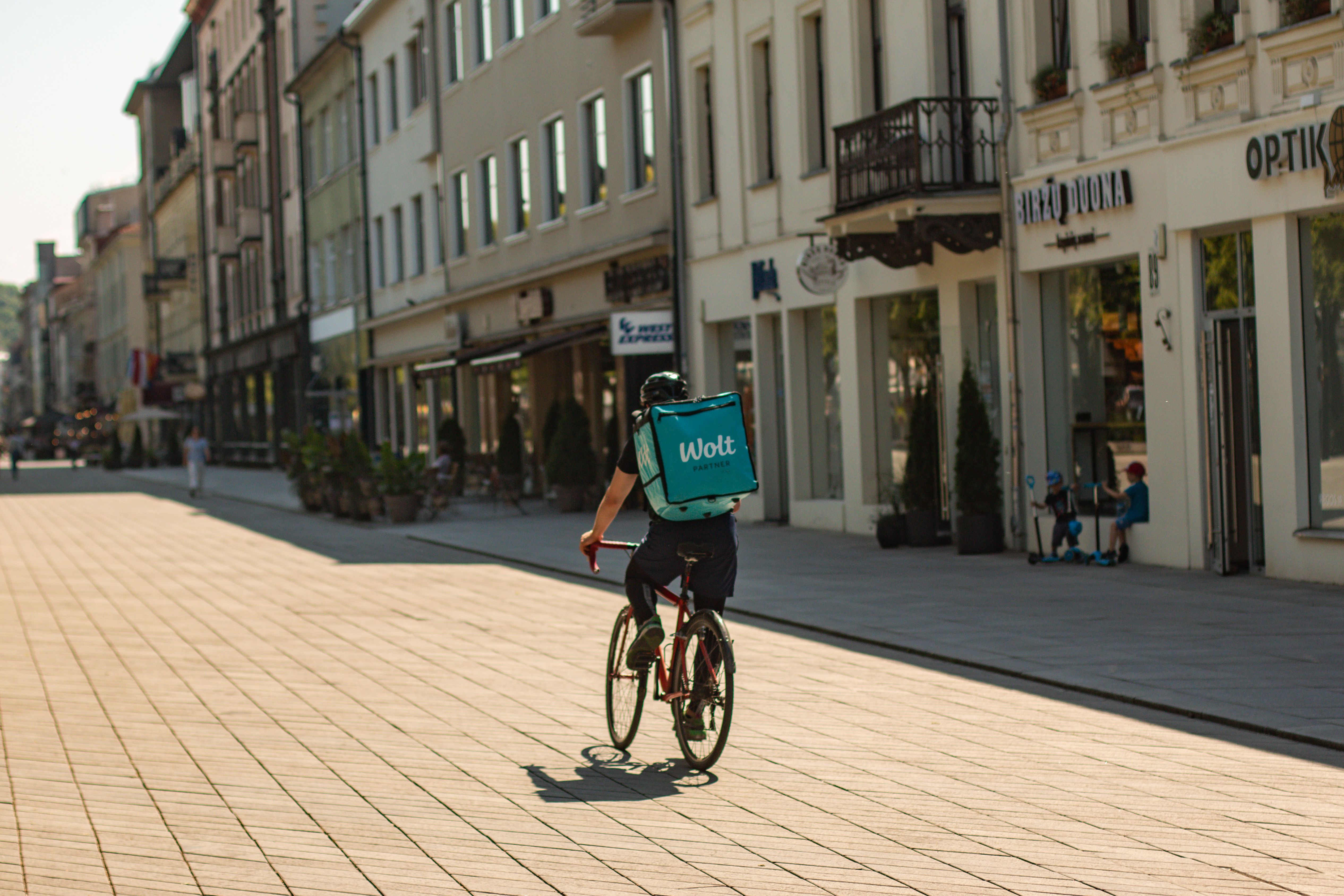 Urban Food Delivery Cyclist on Sunny Street · Free Stock Photo