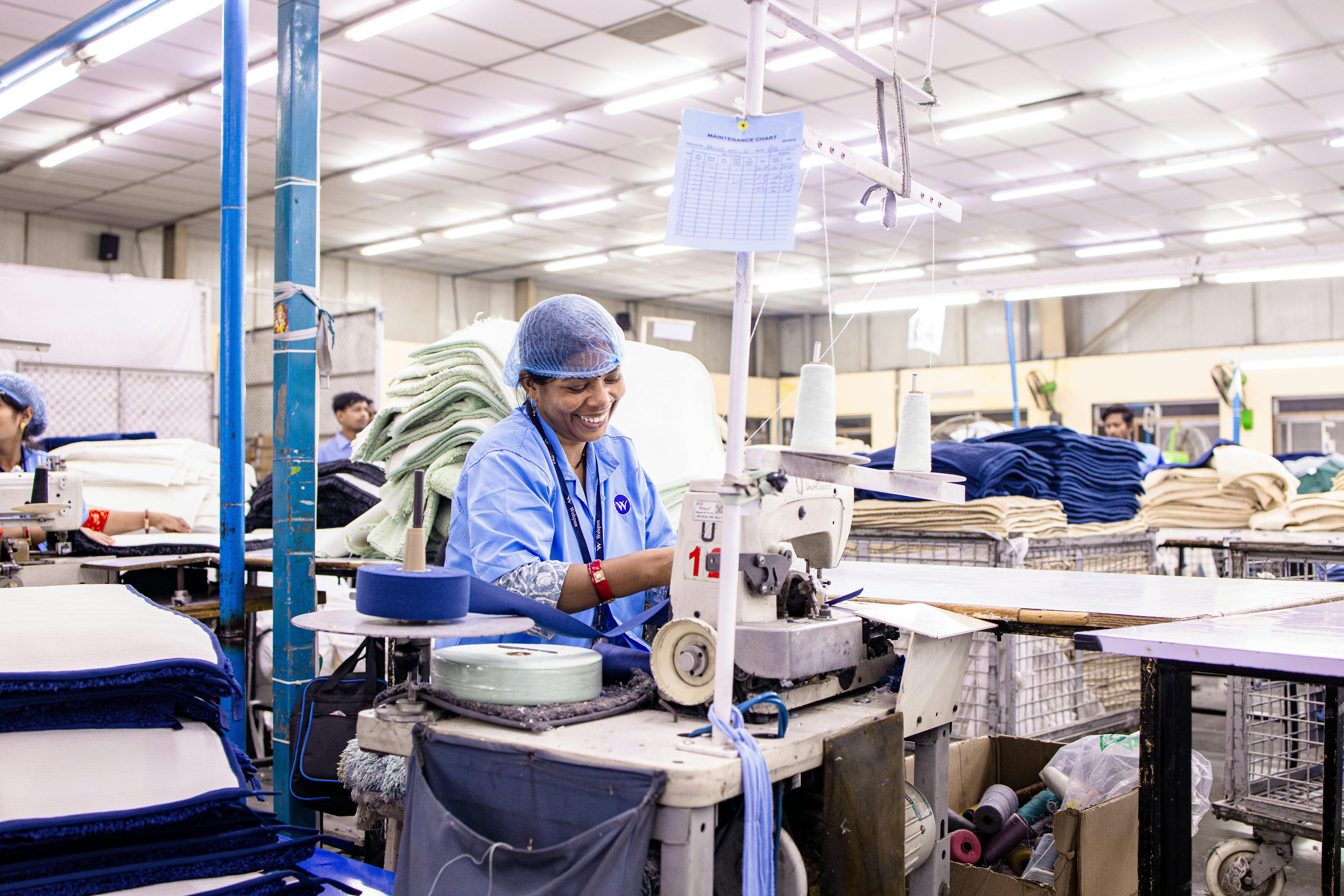 Smiling Factory Worker Operating Sewing Machine · Free Stock Photo