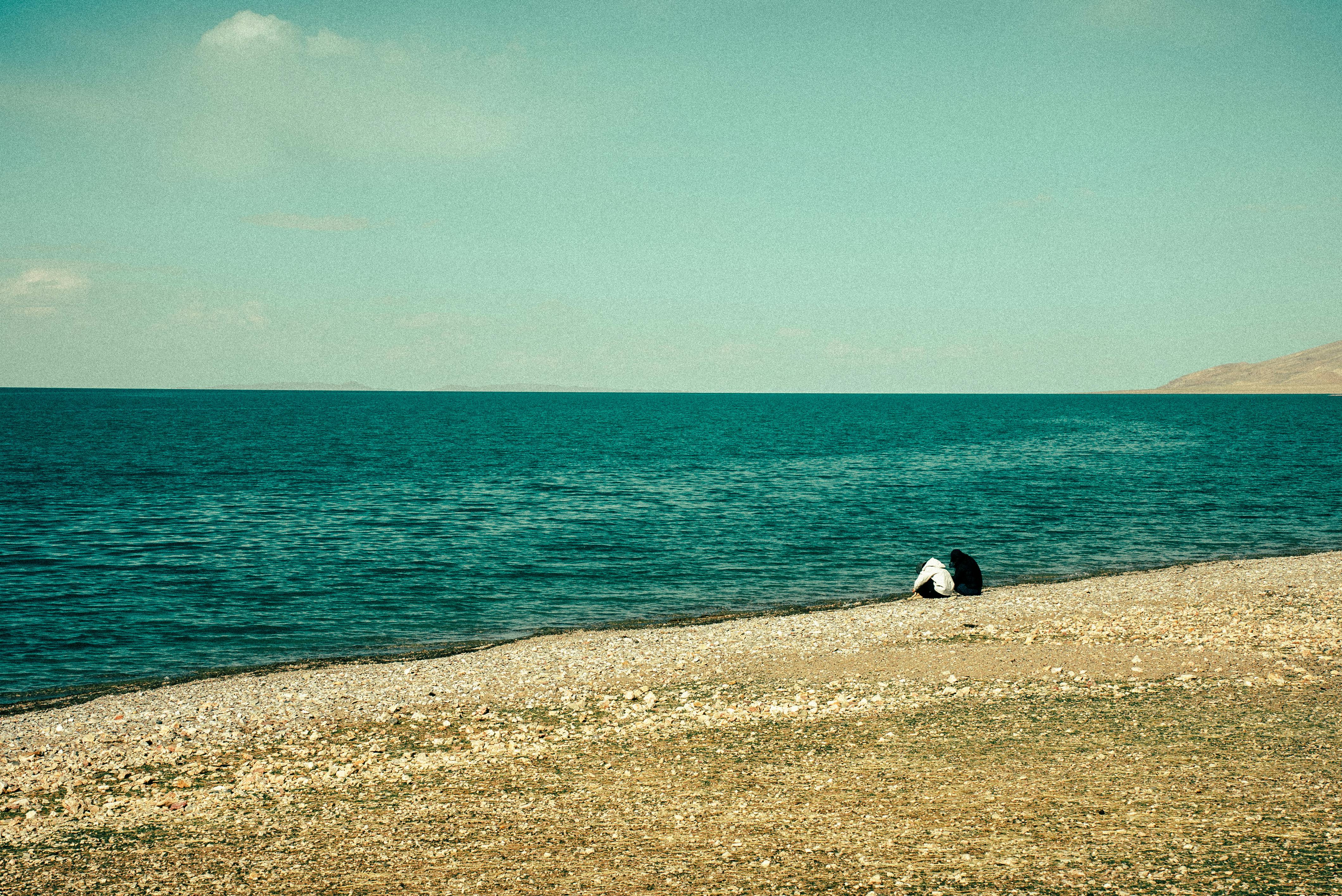 Serene Beachfront with a Couple by the Sea · Free Stock Photo