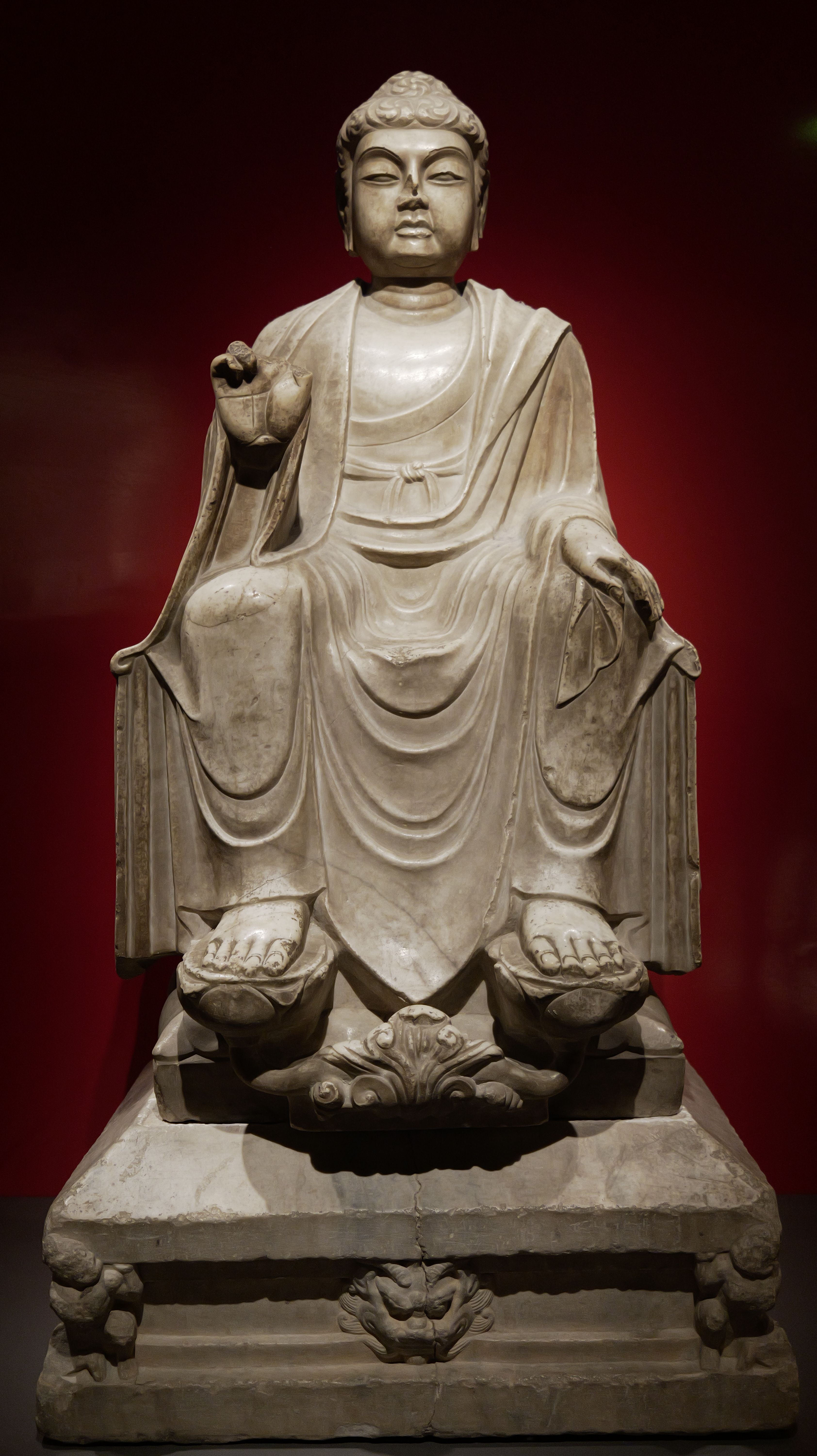 Ancient Buddha Statue on Display Against Red Background · Free Stock Photo