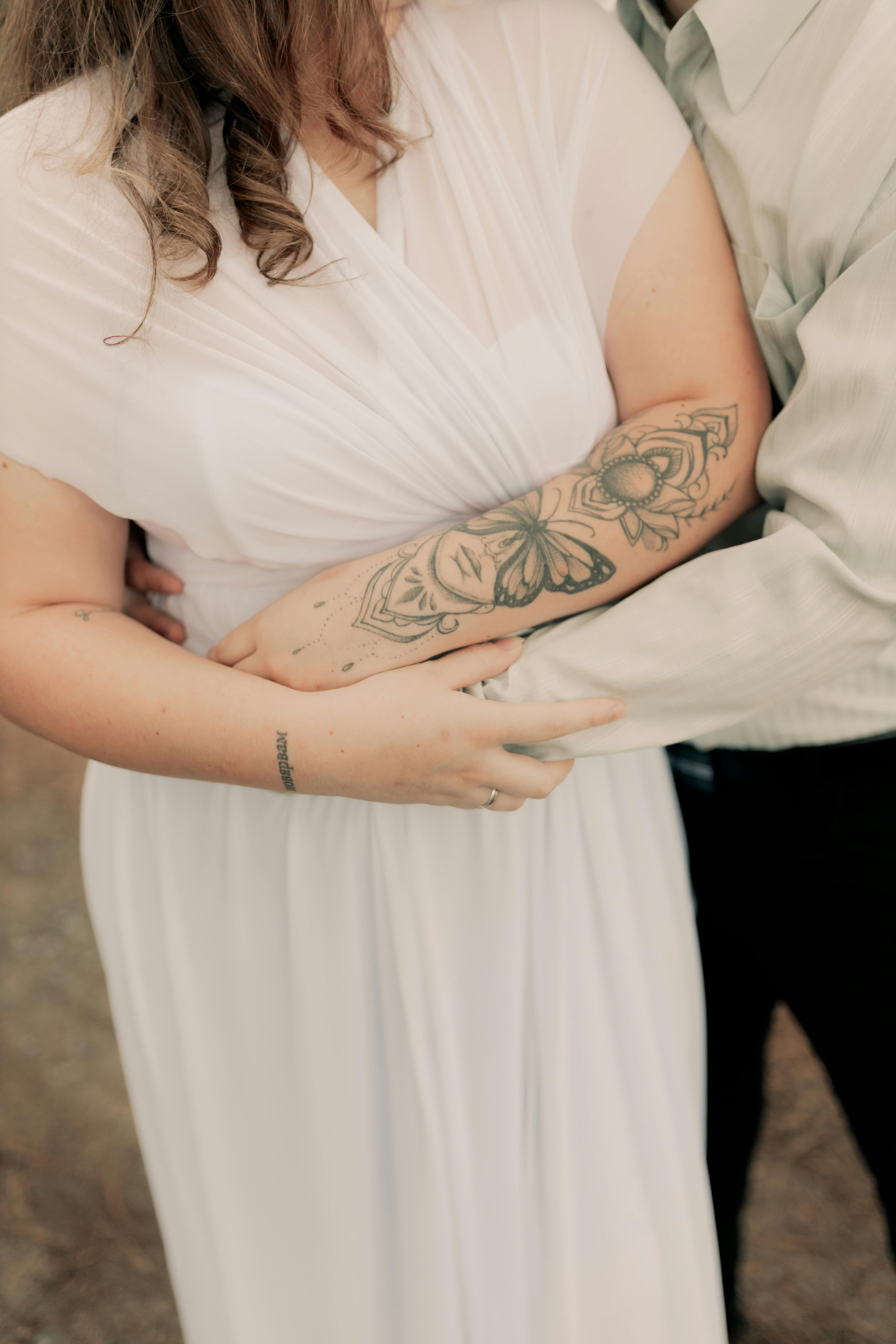 Close-Up of Tattooed Arms Embracing in Wedding Attire · Free Stock Photo