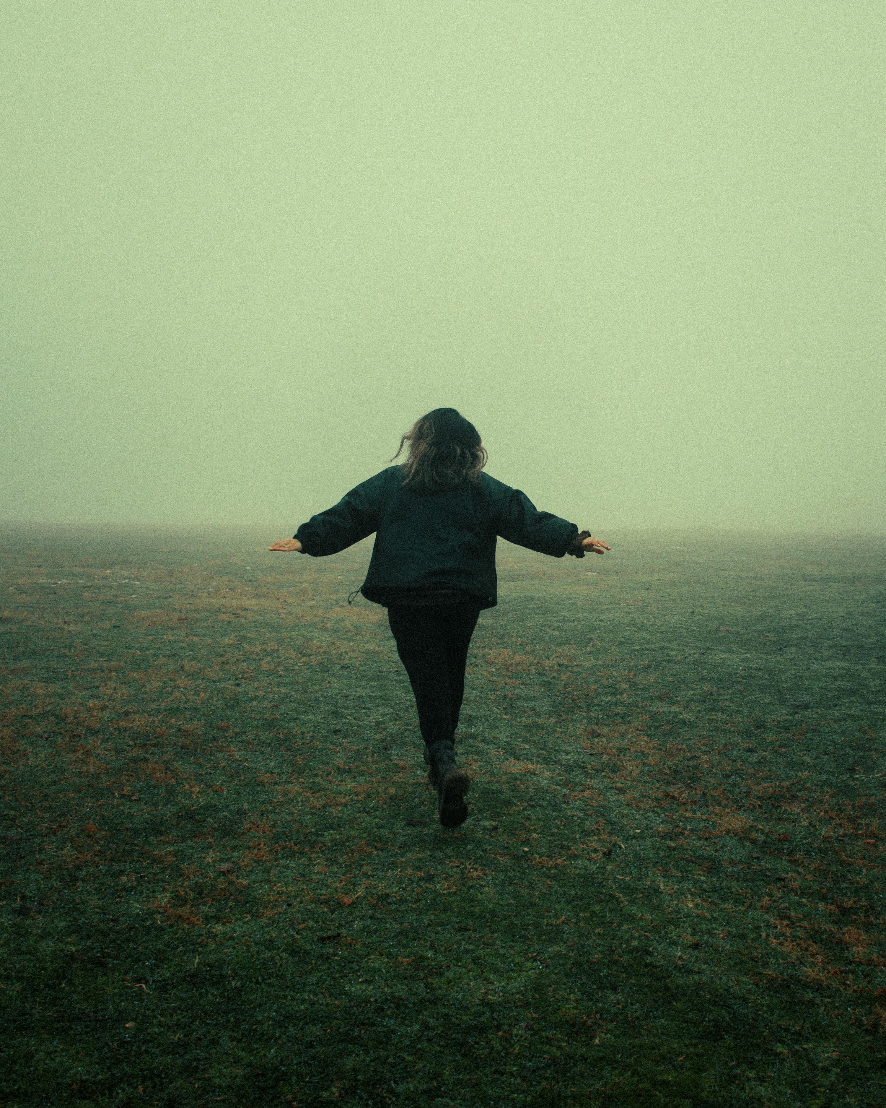 Woman Running Freely in Foggy Field · Free Stock Photo