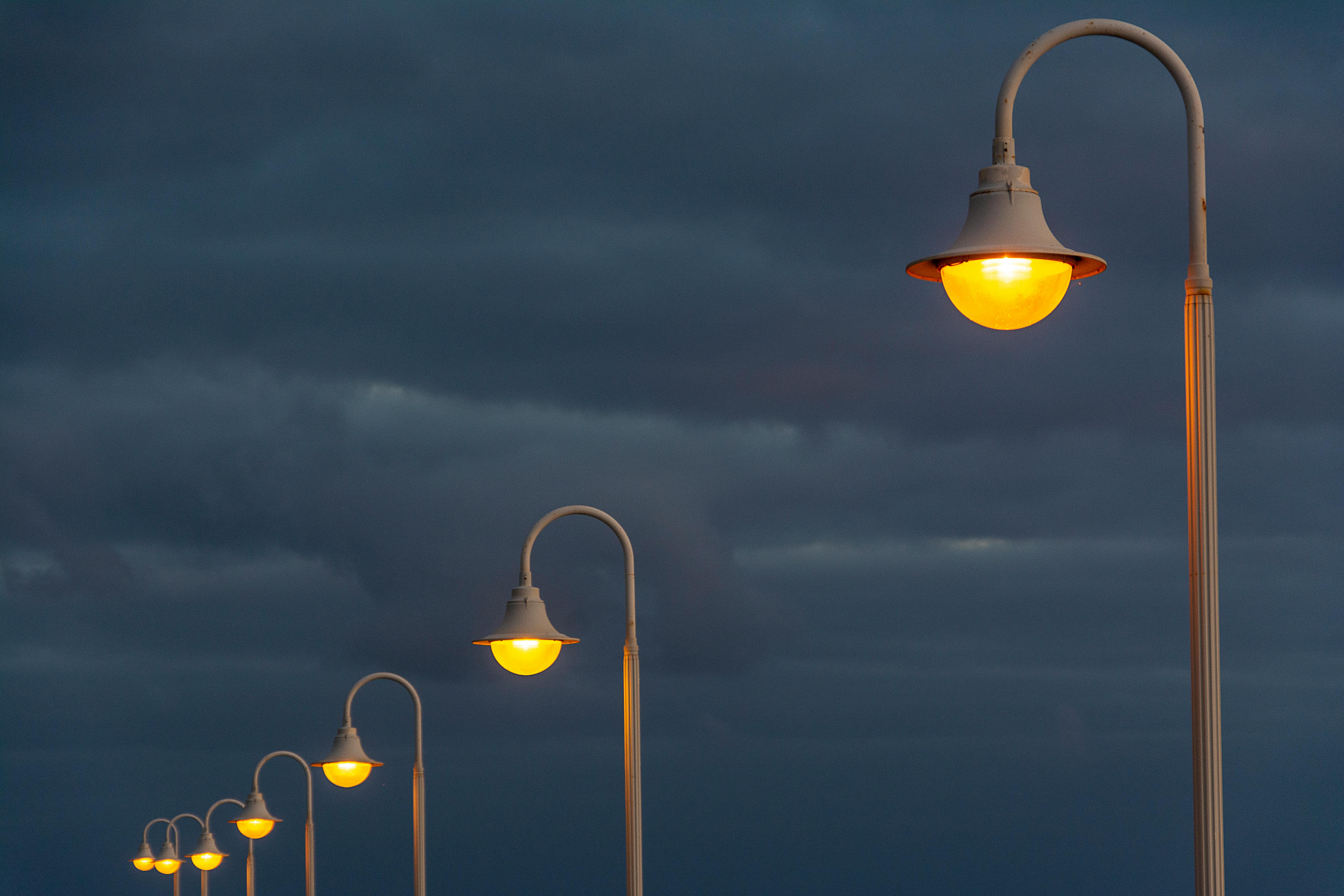 Row of Illuminated Street Lamps Against Night Sky · Free Stock Photo