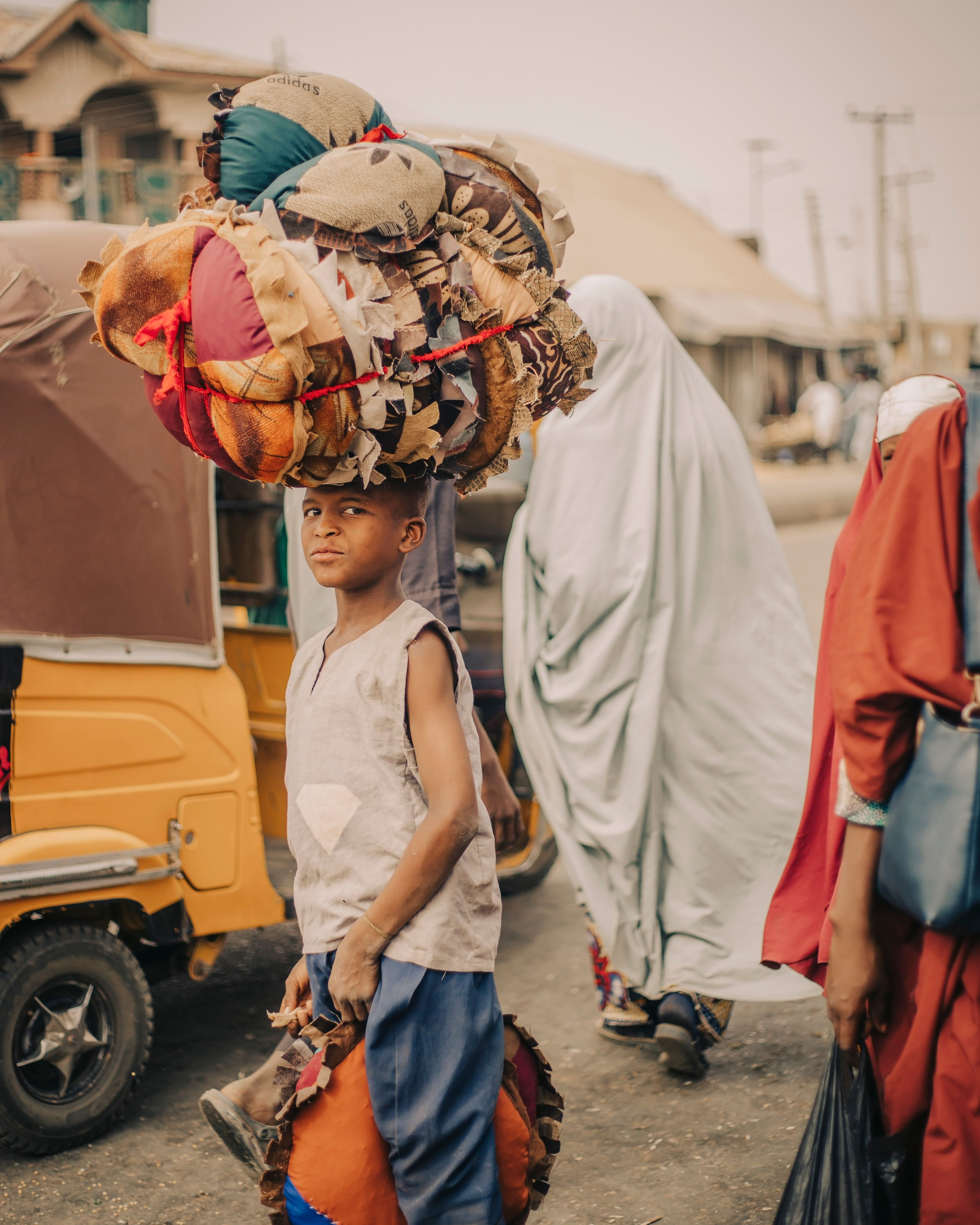 Young Boy Balancing Goods in Bustling Market Scene · Free Stock Photo