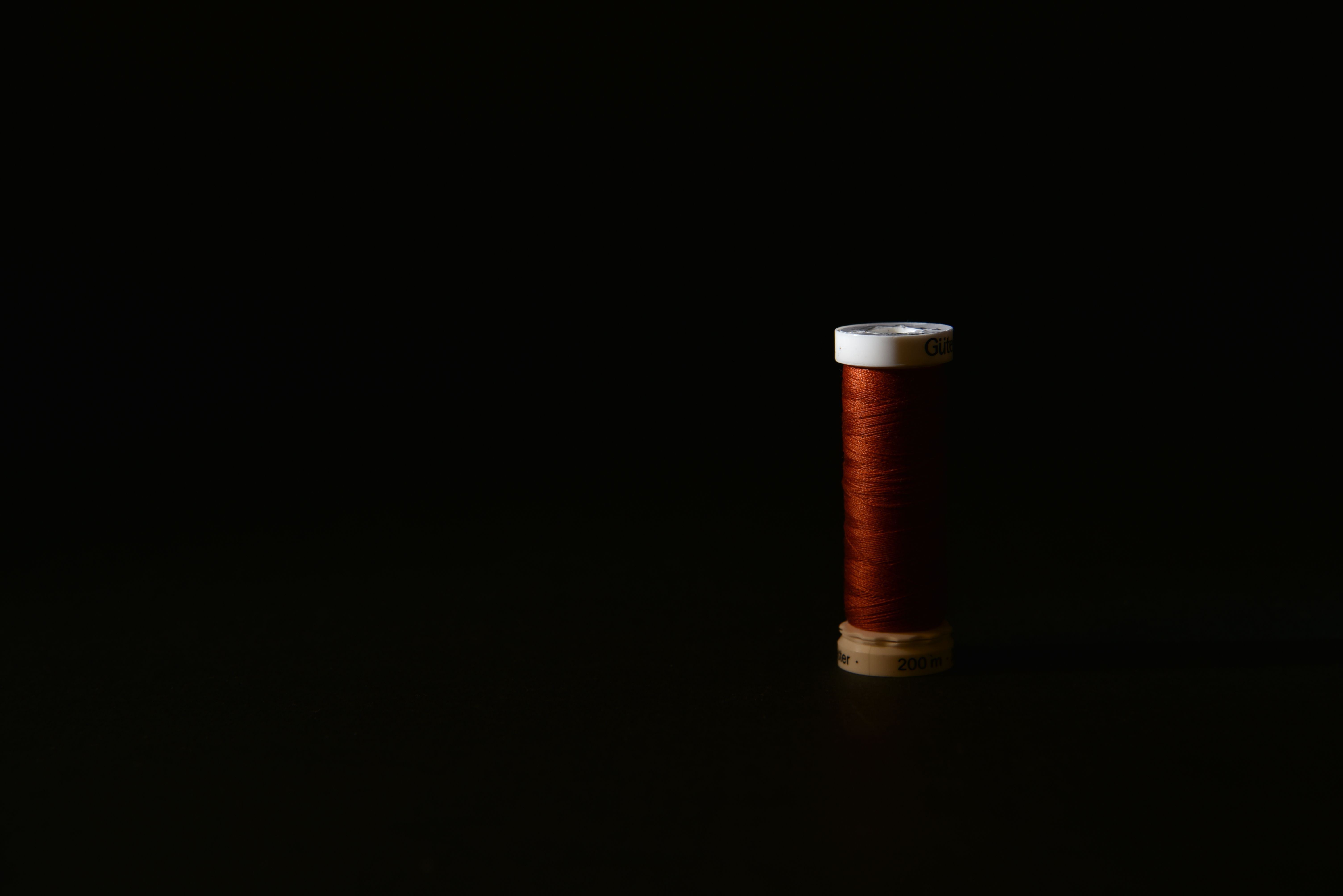 Elegant Minimalist Spool of Thread on Dark Background · Free Stock Photo