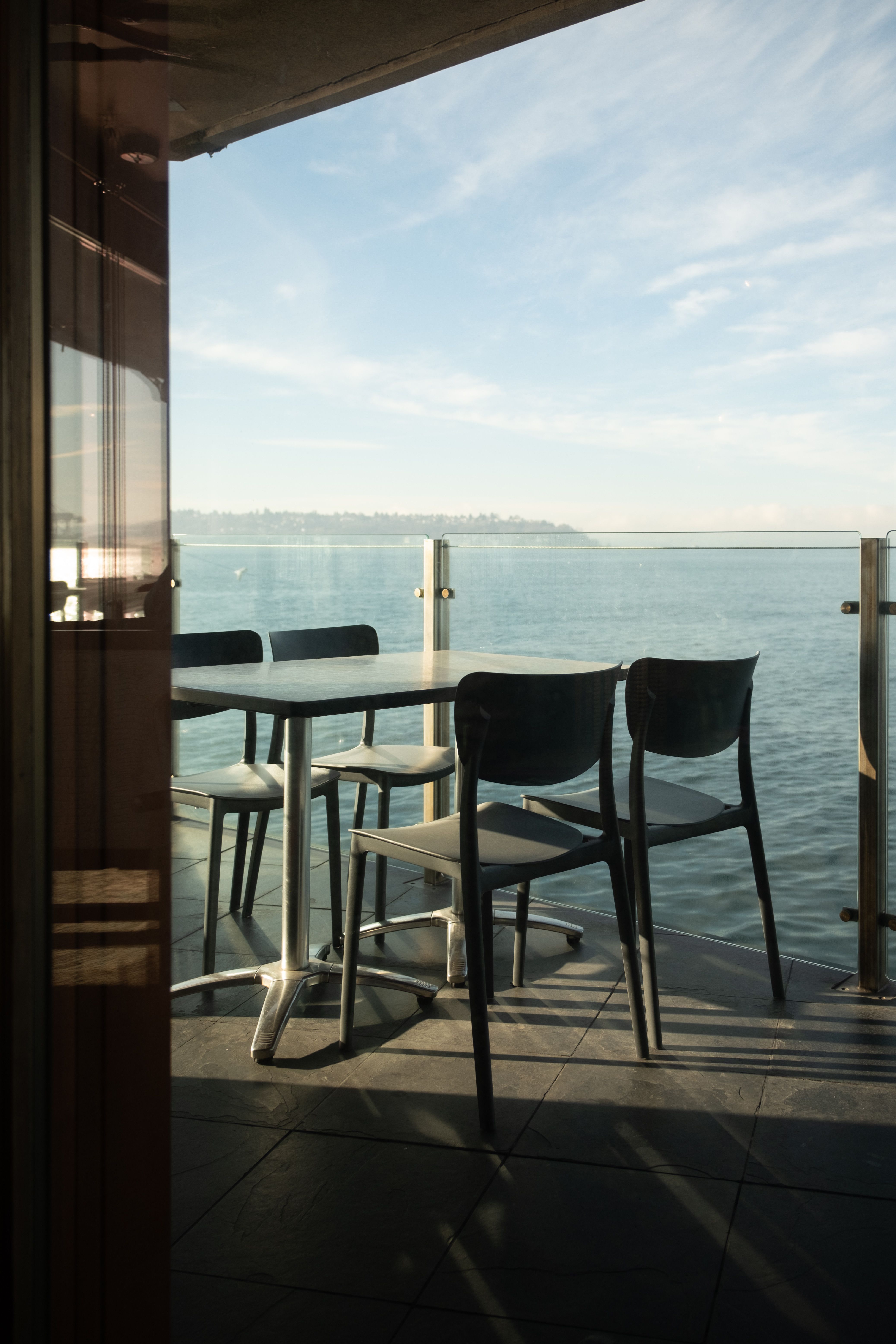 Serene Lakefront Balcony with Empty Dining Chairs · Free Stock Photo