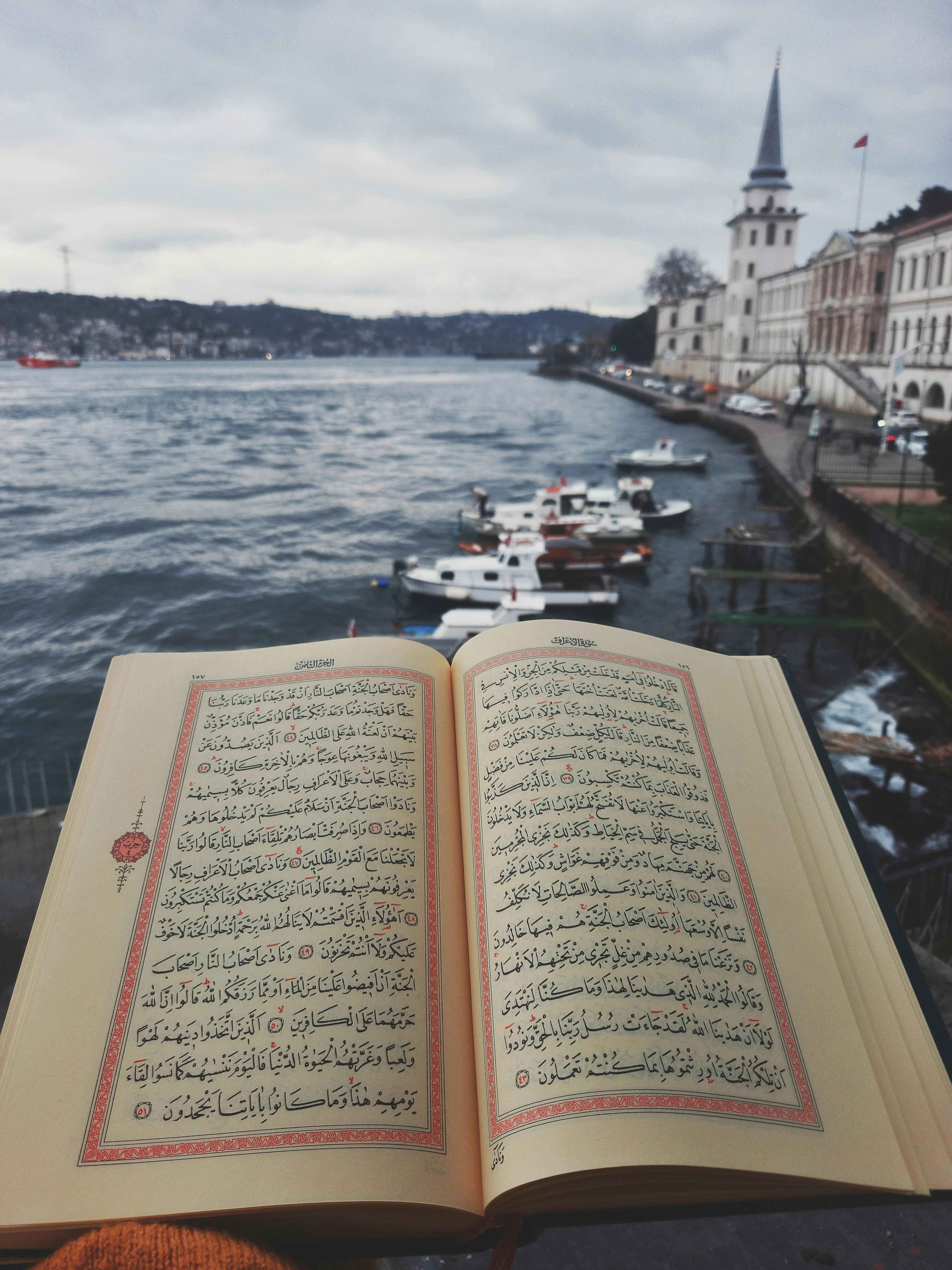 Open Quran with View of Mosque by the Water · Free Stock Photo