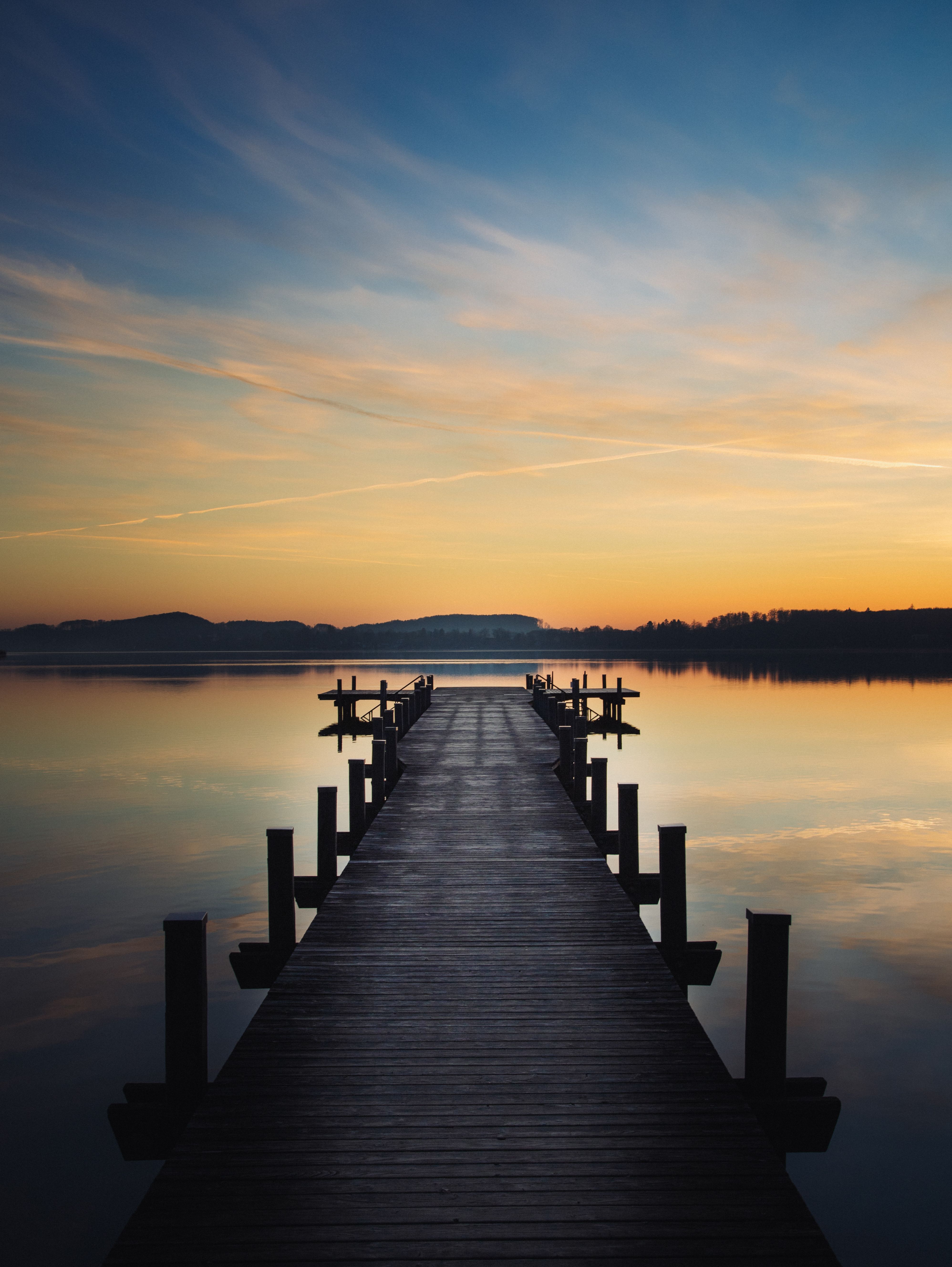 A wooden pier at sunset with water in the background · Free Stock Photo