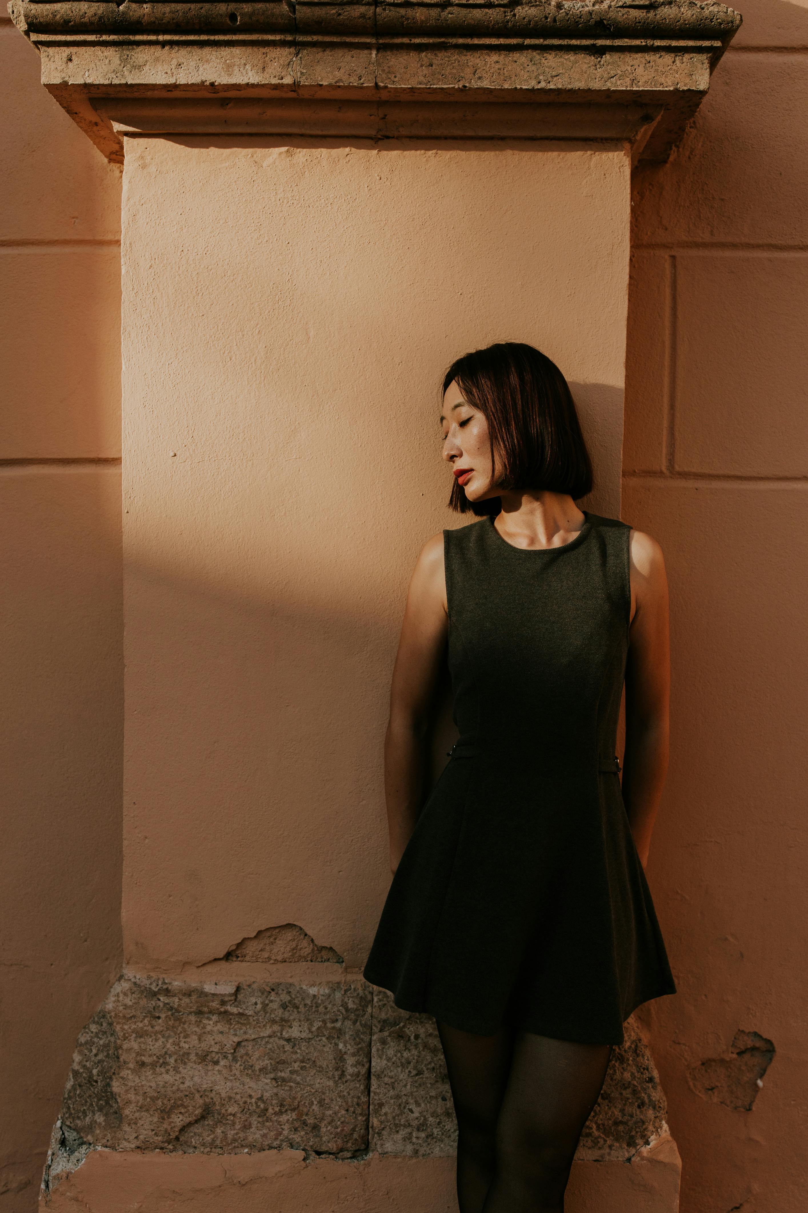 Stylish Woman in Shadow Against Rustic Wall · Free Stock Photo