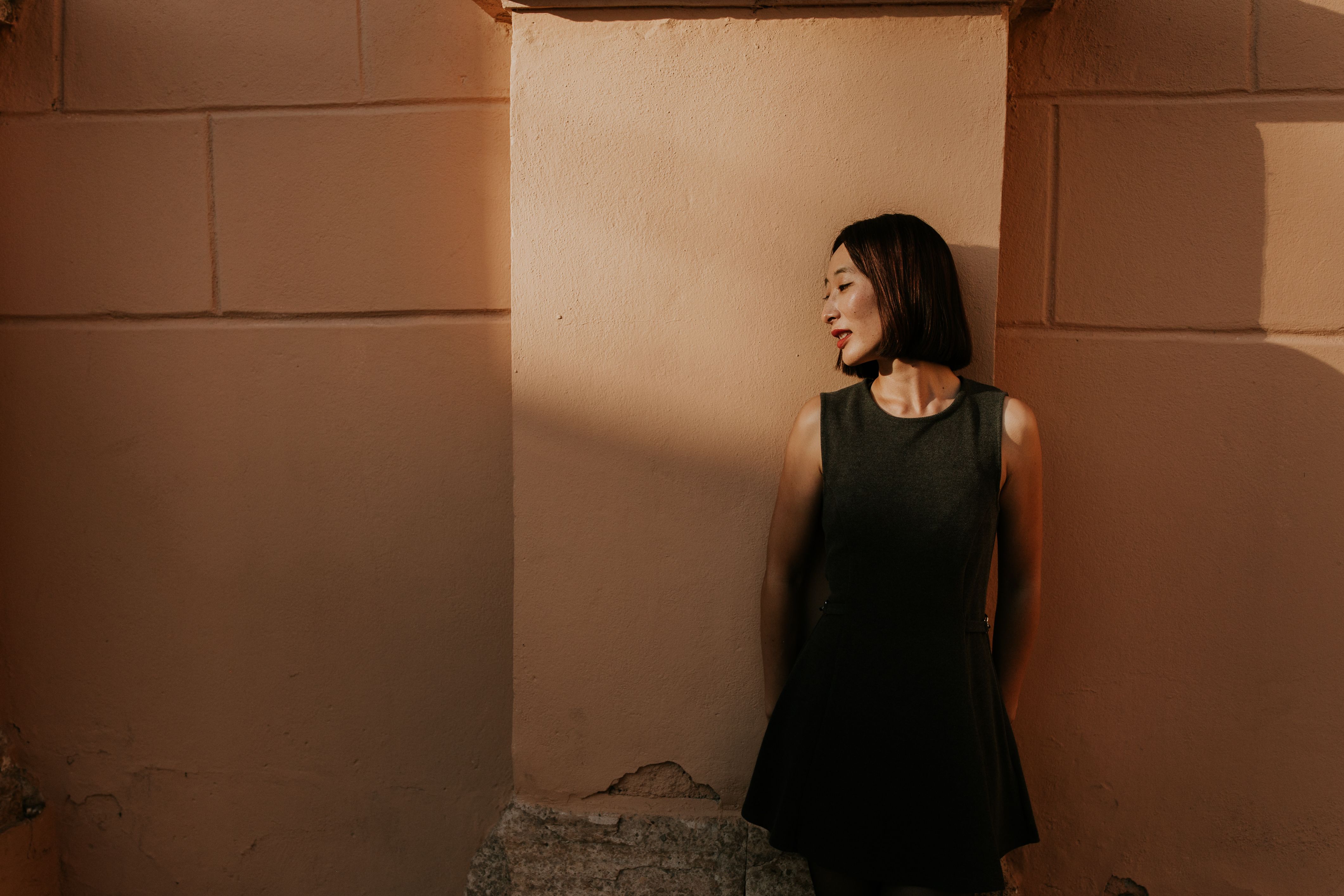 Elegant Woman Posing in Shadows Against Wall · Free Stock Photo