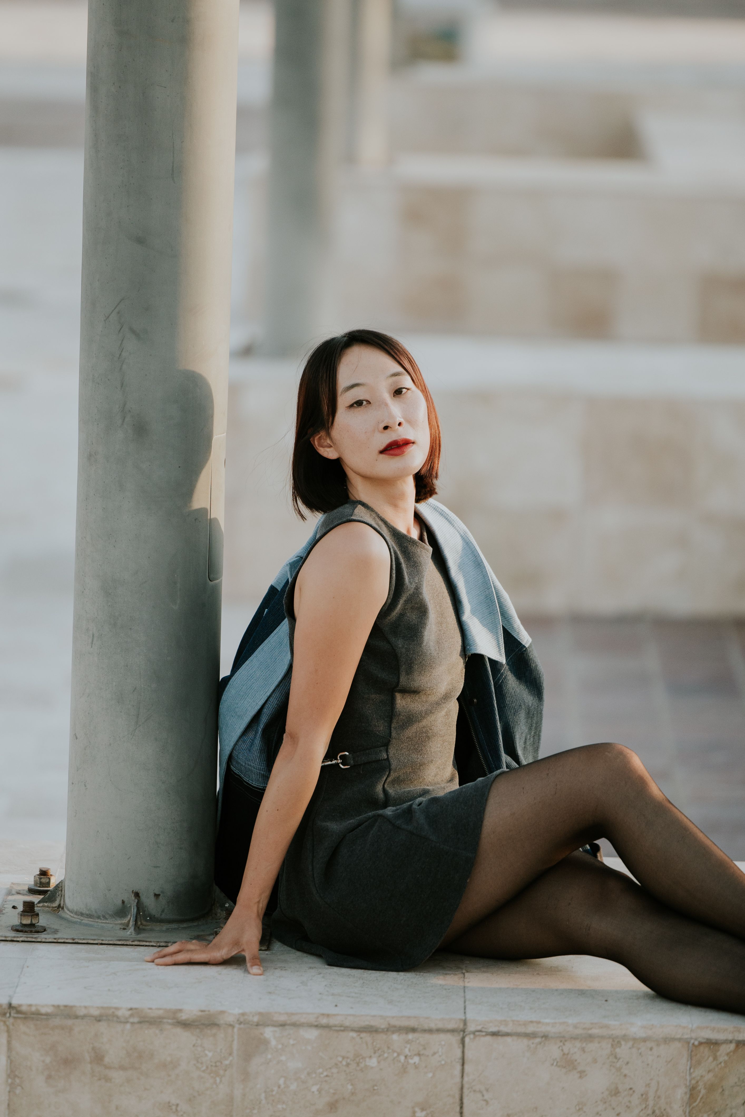 Elegant Woman Posing by Pillar in Urban Setting · Free Stock Photo