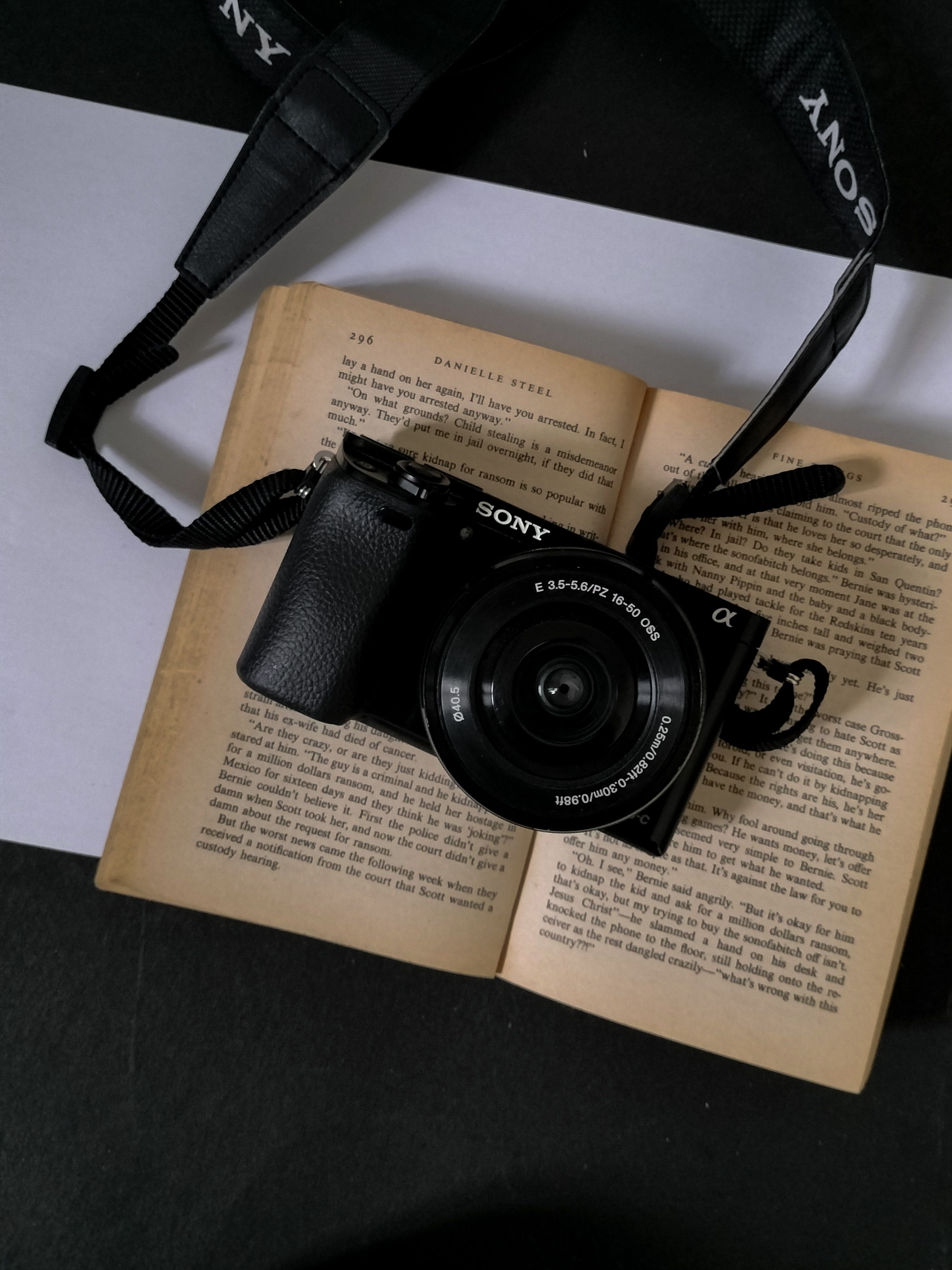 Open Book with Sony Camera on Dark Surface · Free Stock Photo