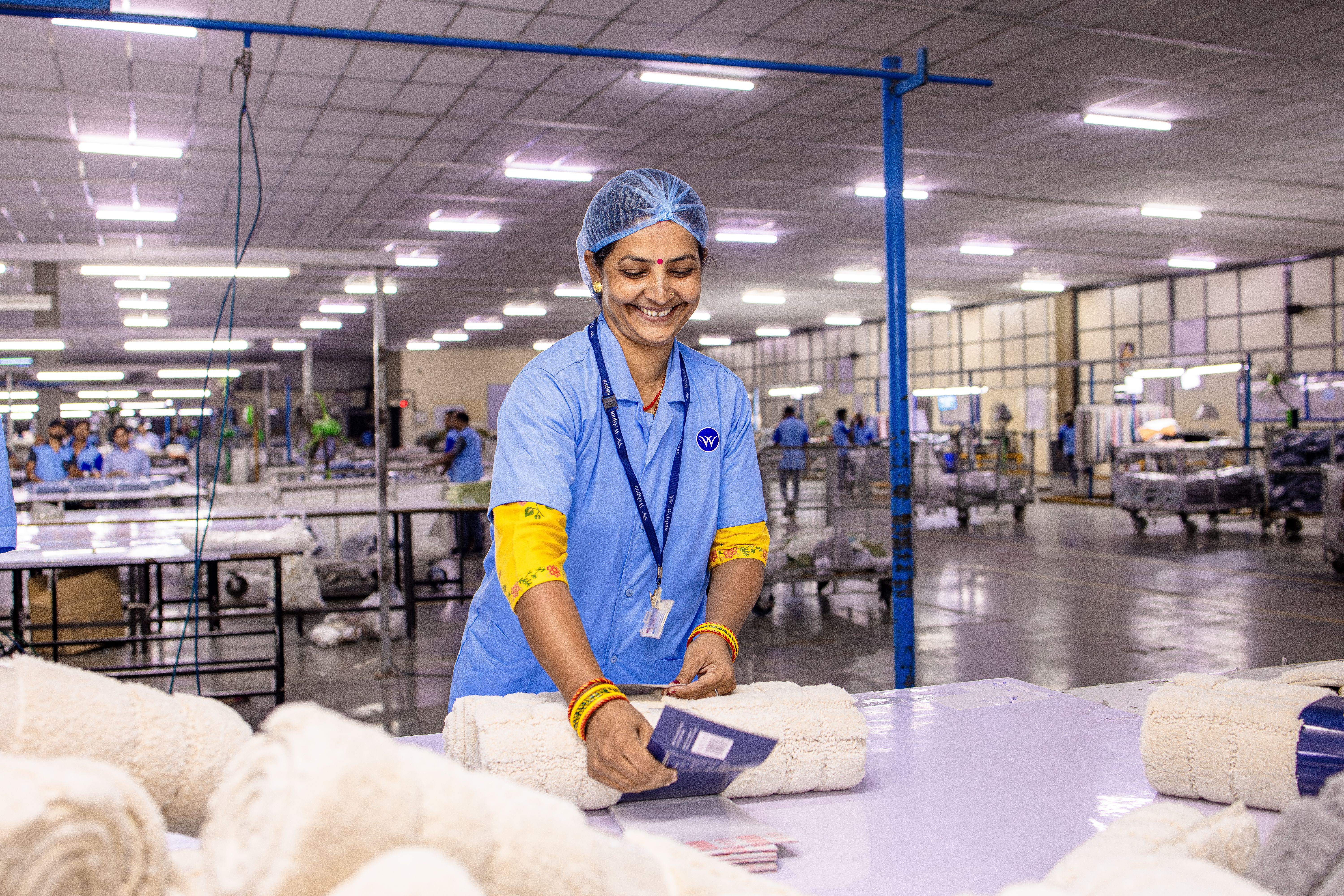 Smiling Factory Worker Handling Textile Products · Free Stock Photo