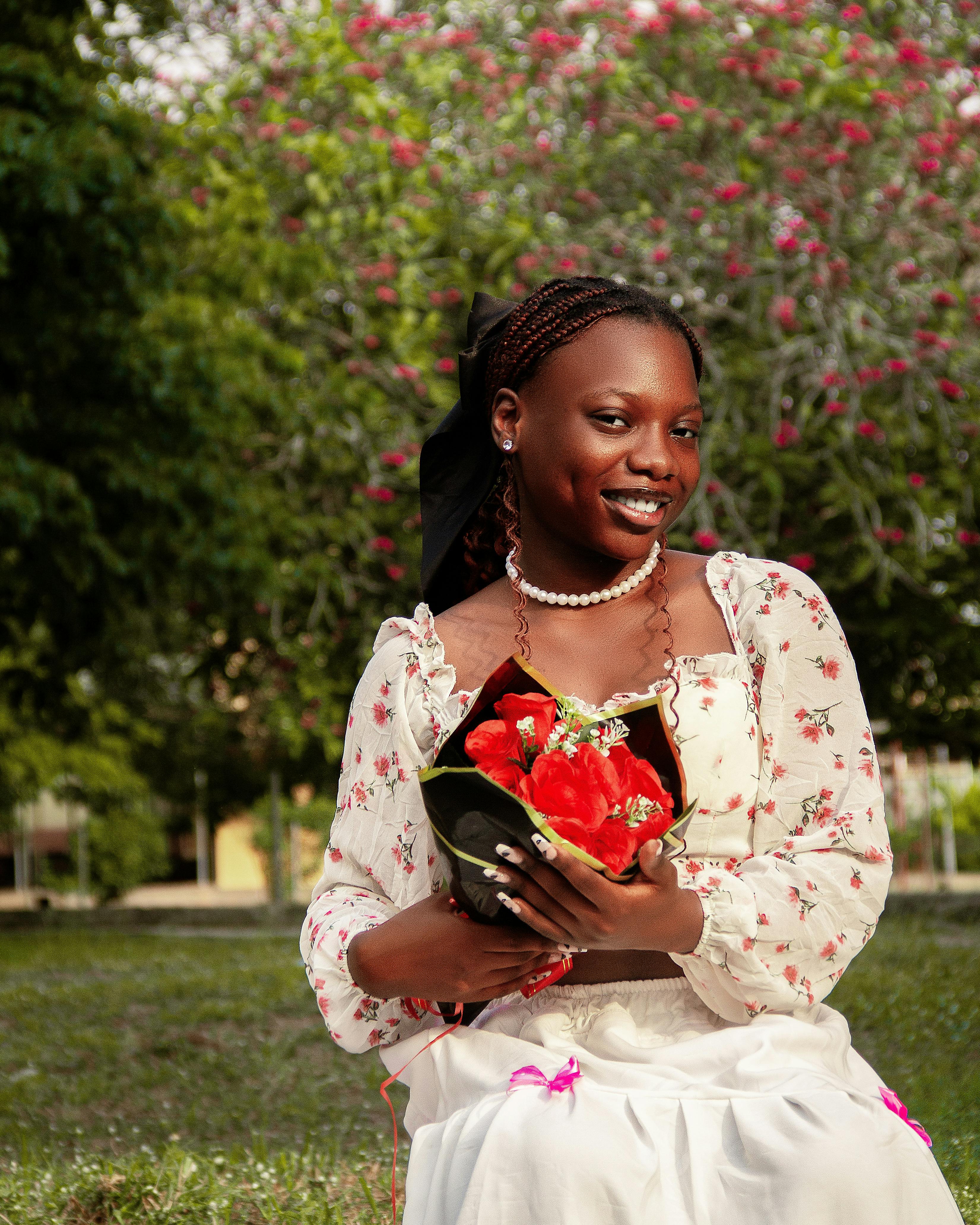 Young Woman in Floral Dress Holding Bouquet Outdoors · Free Stock Photo