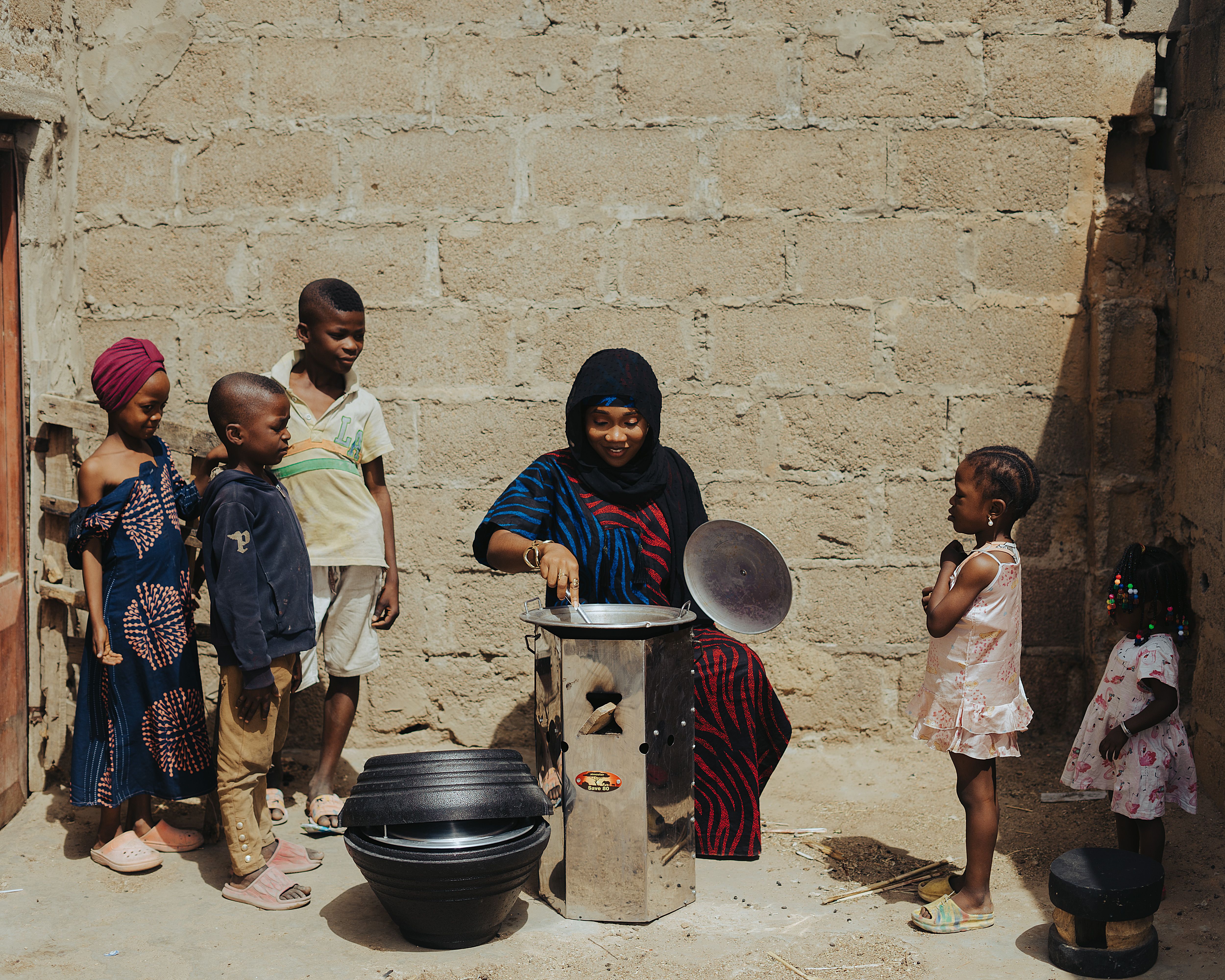 African woman cooking outdoors with children · Free Stock Photo