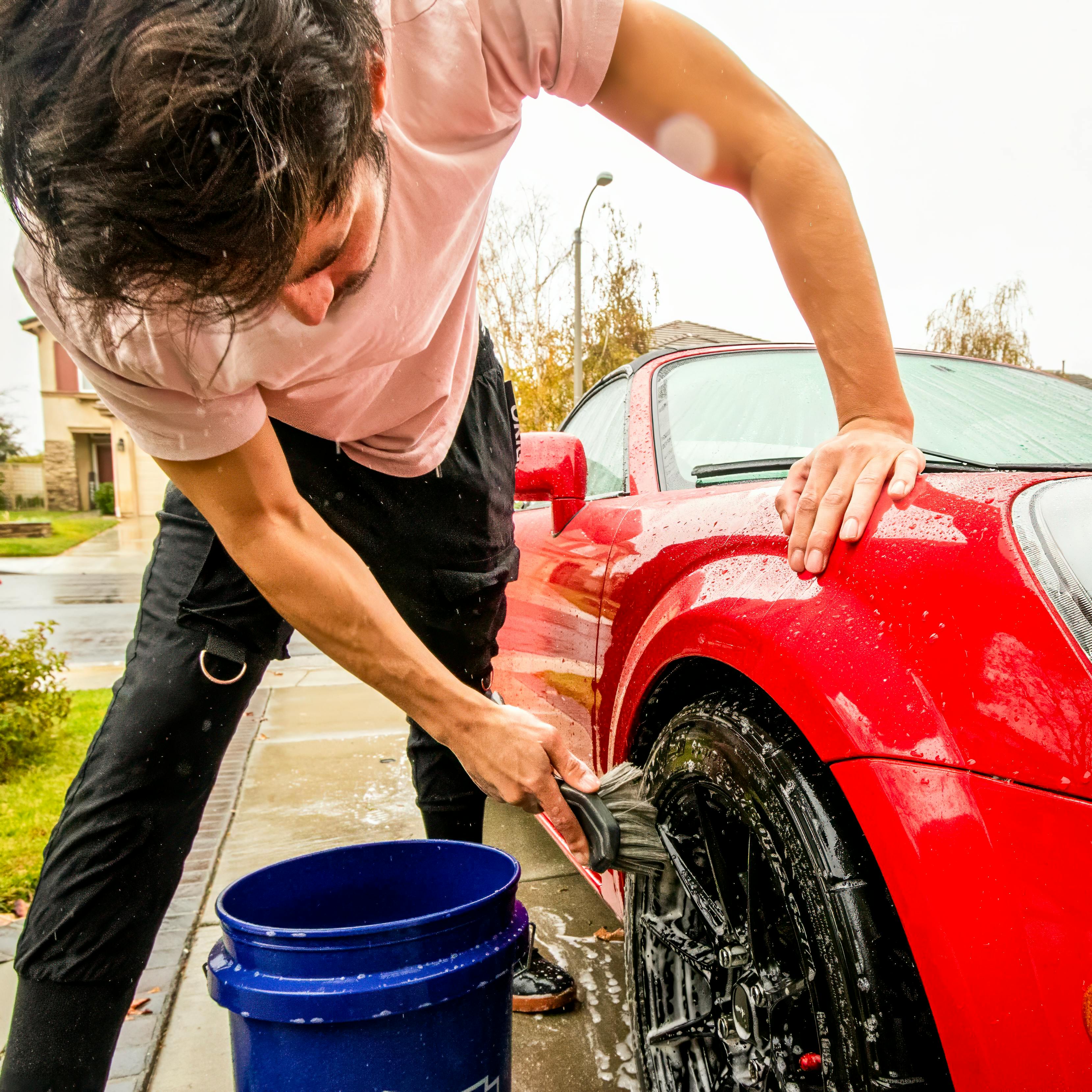 Man Cleaning Red Car on a Rainy Day · Free Stock Photo