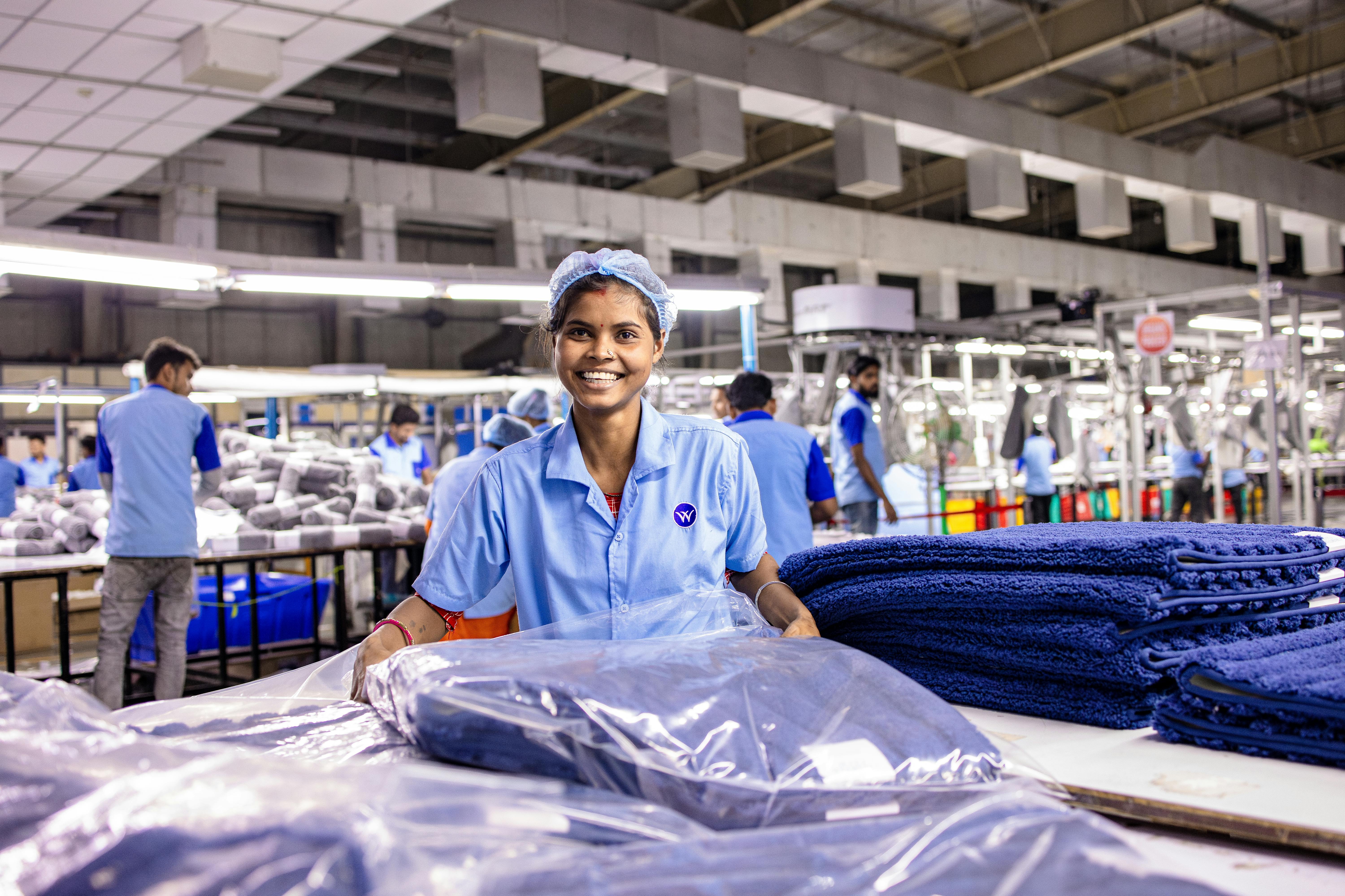 Happy Textile Worker in Busy Factory Setting · Free Stock Photo