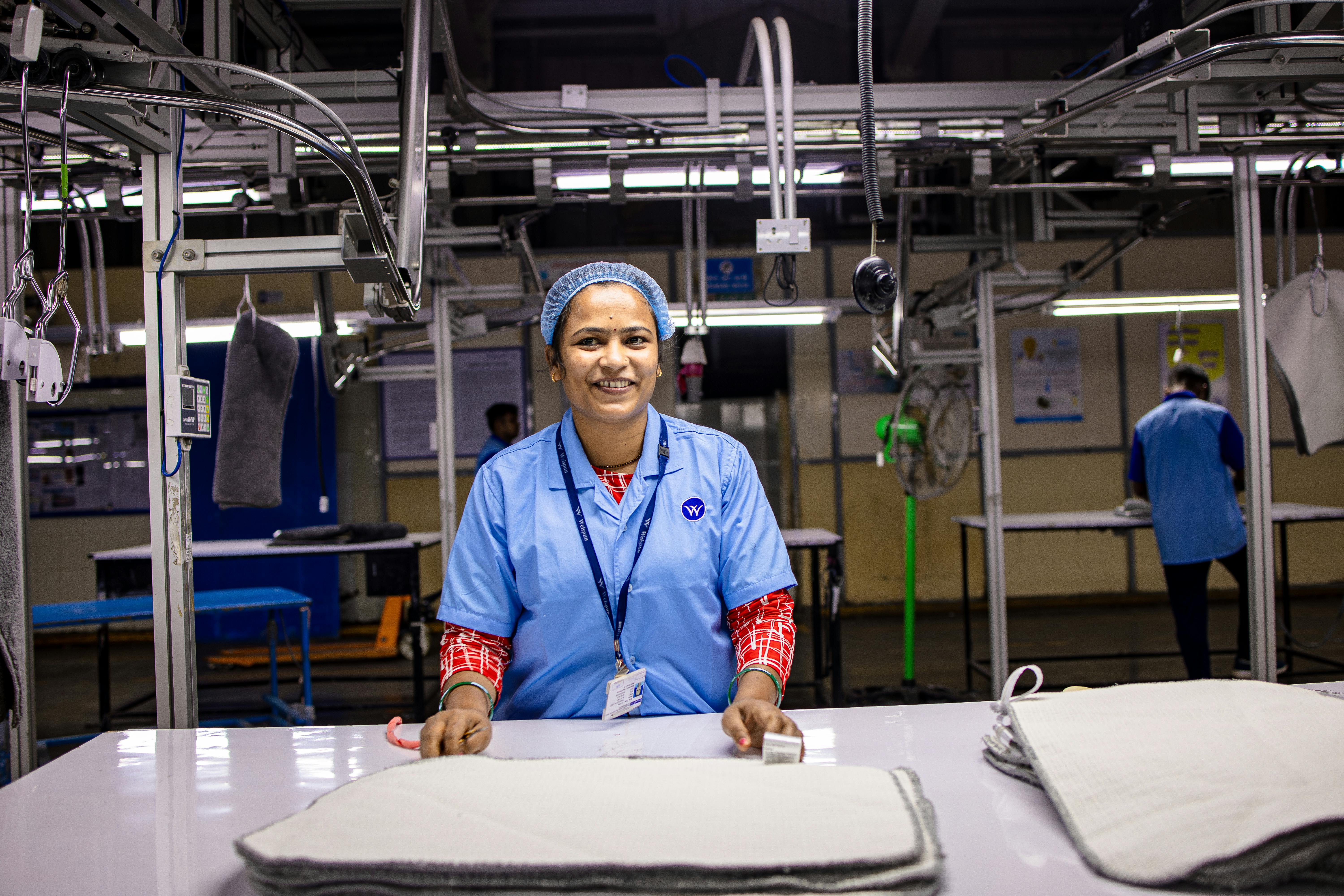 Smiling Textile Worker in Factory Setting · Free Stock Photo