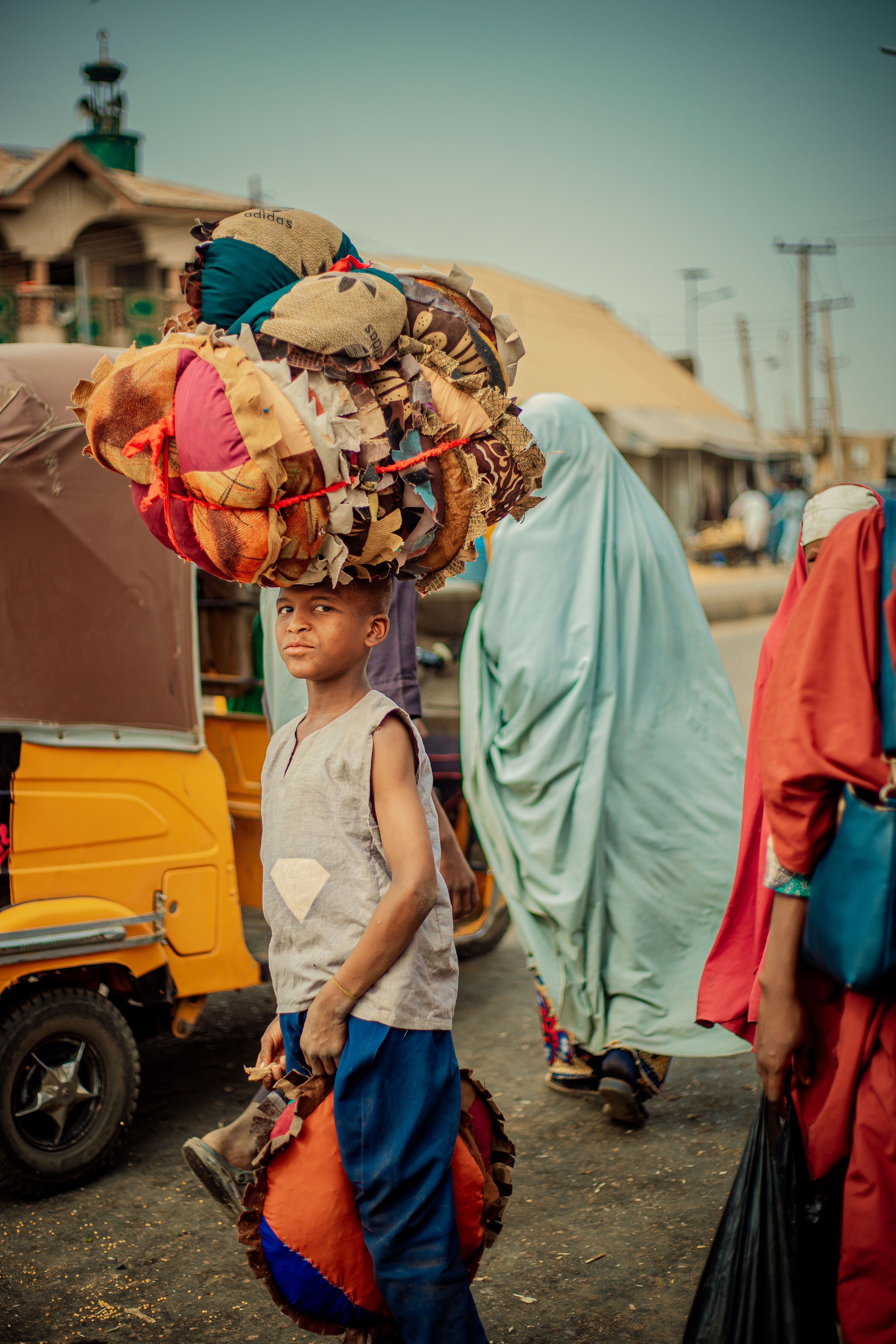 Young Boy Carrying Goods in Vibrant Street Market · Free Stock Photo