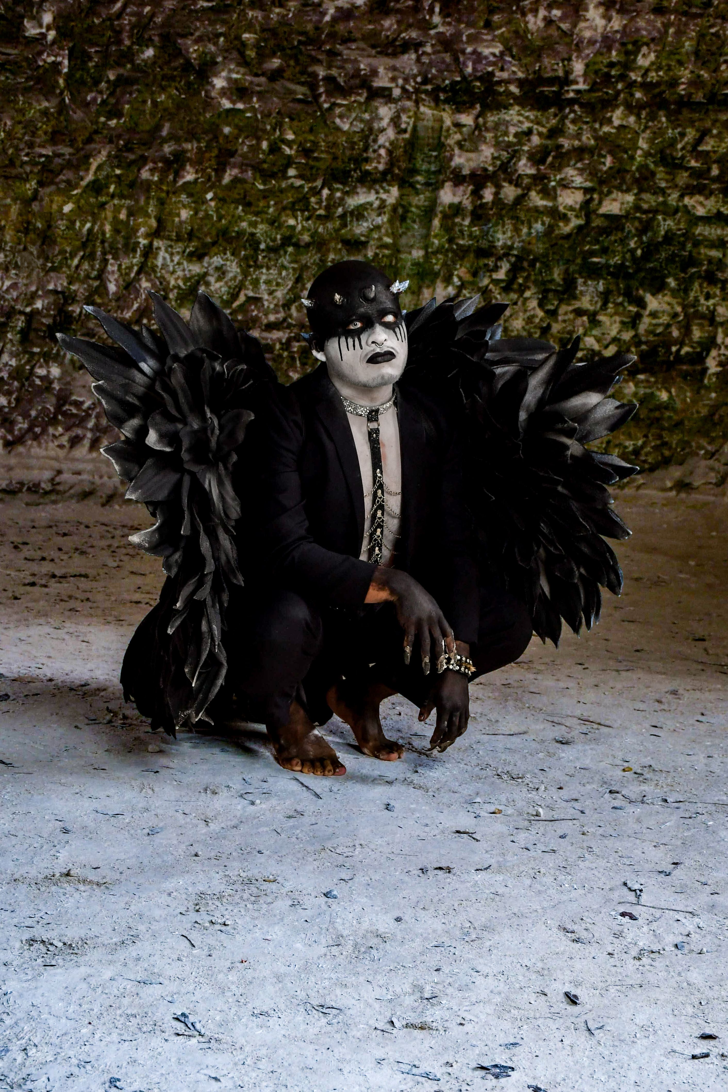 Mystical Figure in Black Winged Costume Crouching · Free Stock Photo