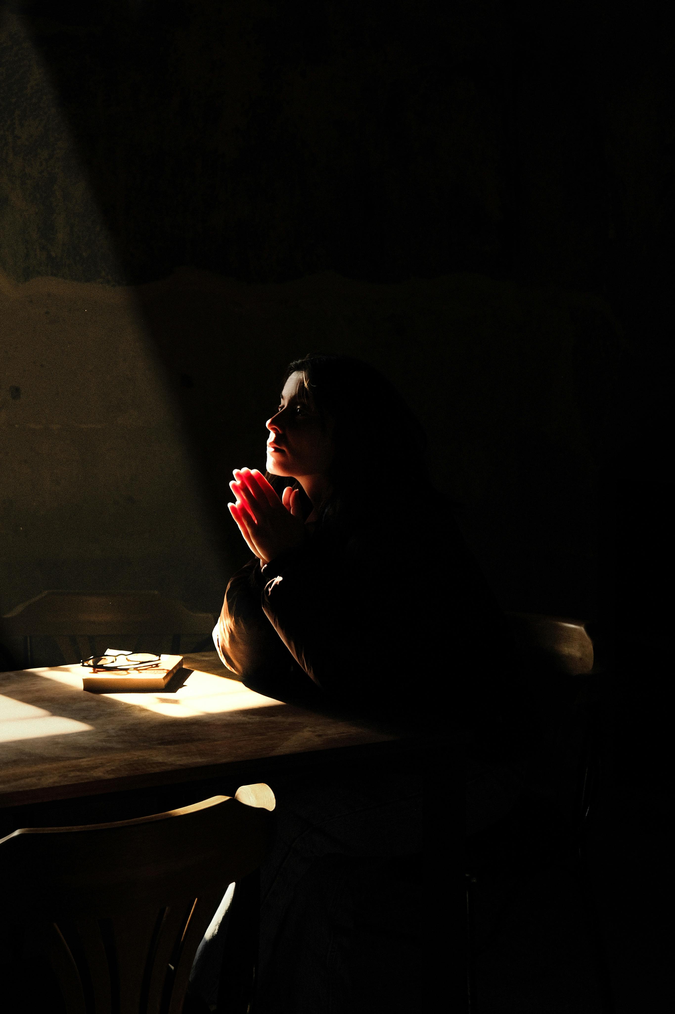 Woman Praying in Dramatic Shadowy Light · Free Stock Photo